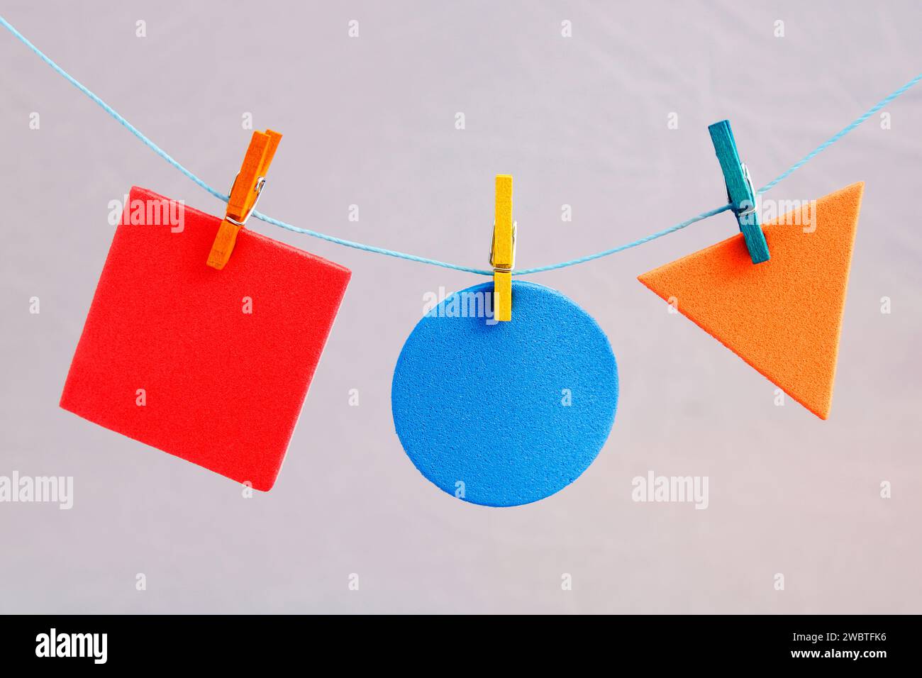 Colored square, circle and triangle attached to string with clothespins ...