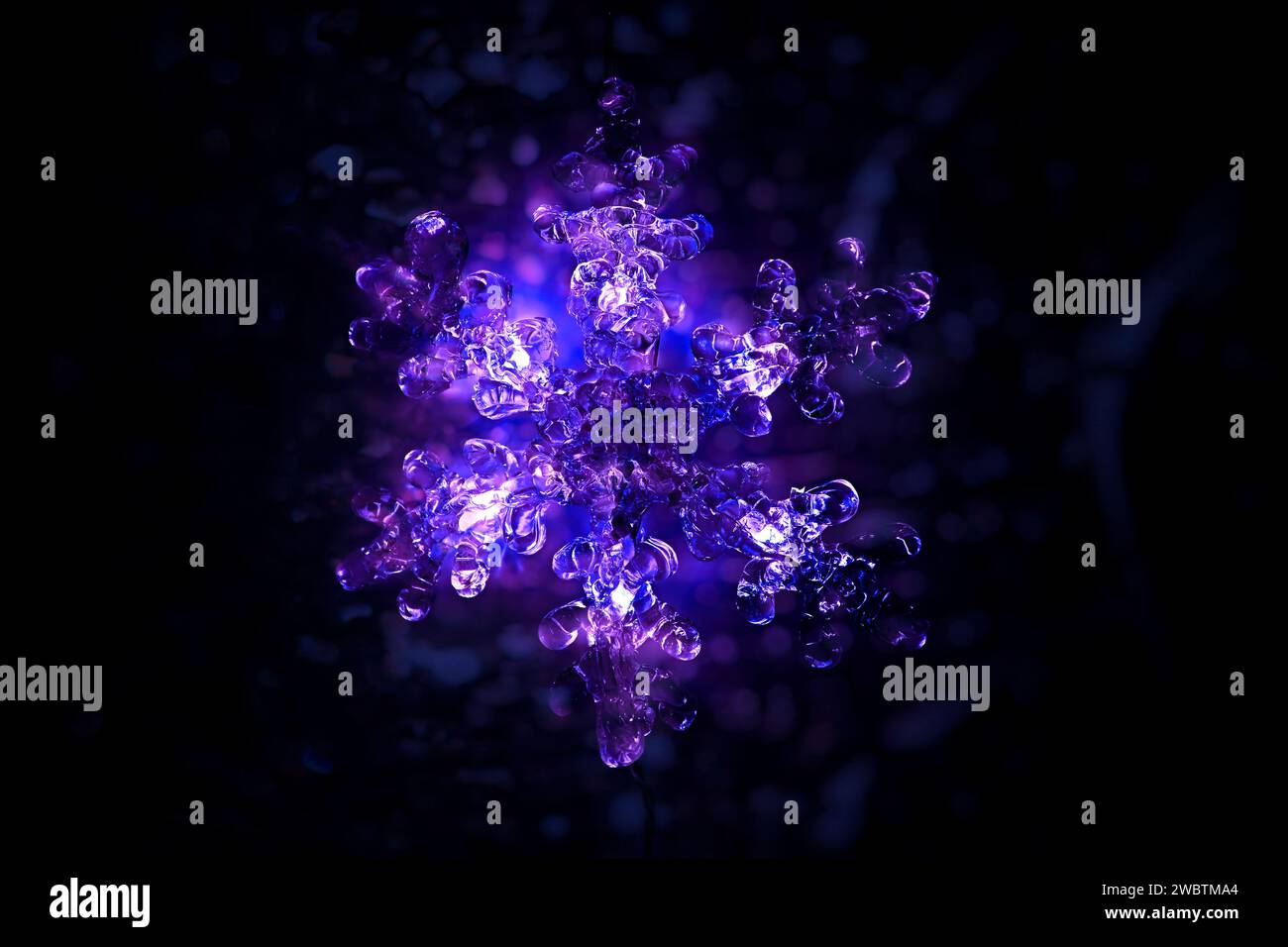 Decorative purple Christmas light in shape of a snowflake illuminated ...