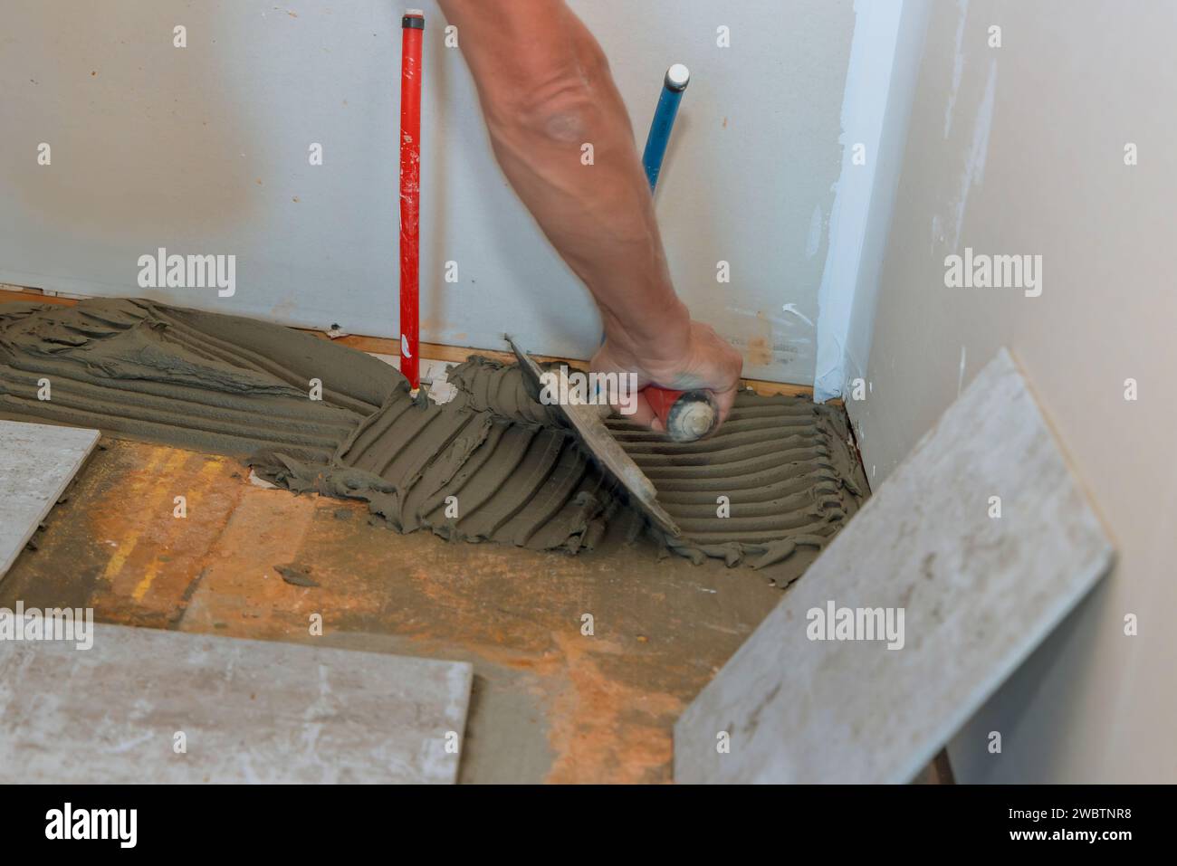 Applying adhesive to concrete floor prior to laying tile Stock Photo ...