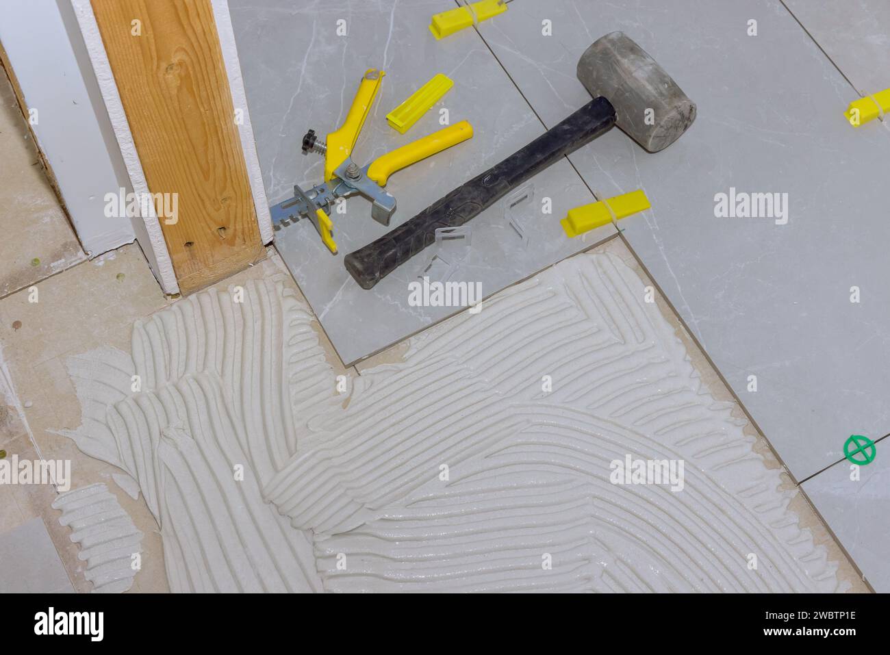 During installation of large tiles, tiler works over mortar adhesive ...