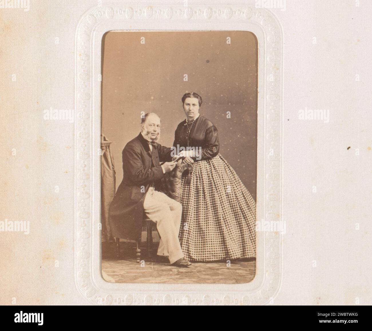 Portrait of a couple, the man sitting on a chair and the woman standing ...
