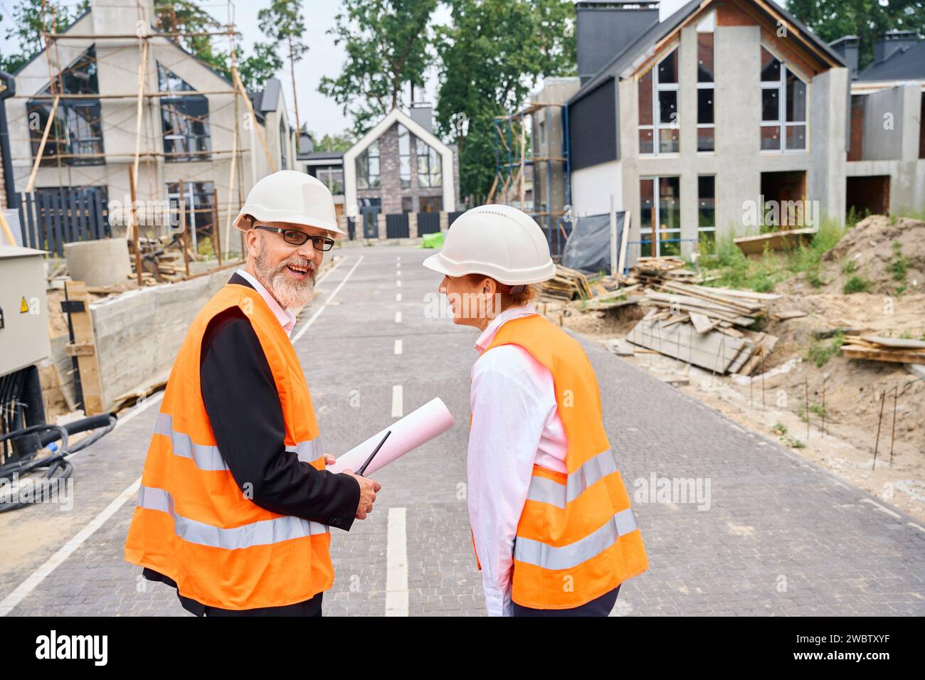 Cheerful construction staff in front of half-built residential houses ...
