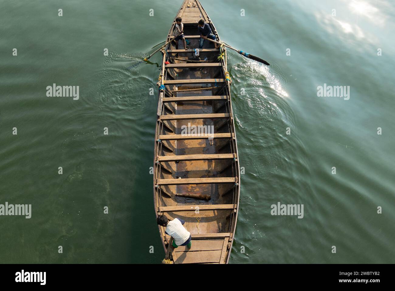 Top view of a wooden boat rowing on green water by a group of children ...