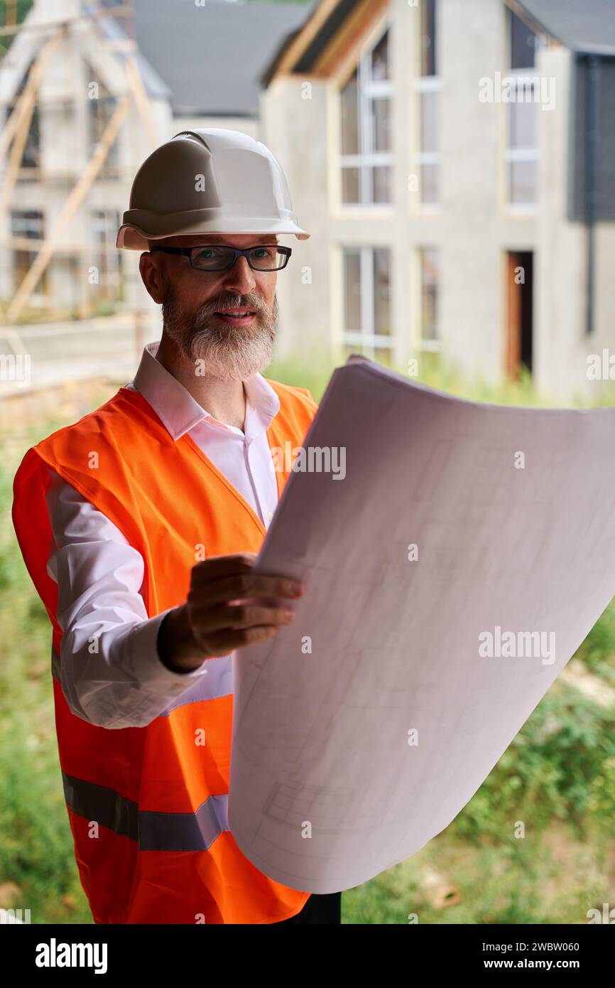 Construction foreman using blueprints on building site Stock Photo - Alamy