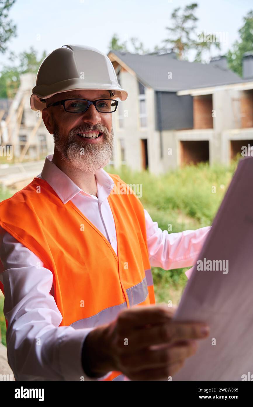 Building contractor with architectural drawings standing on ...