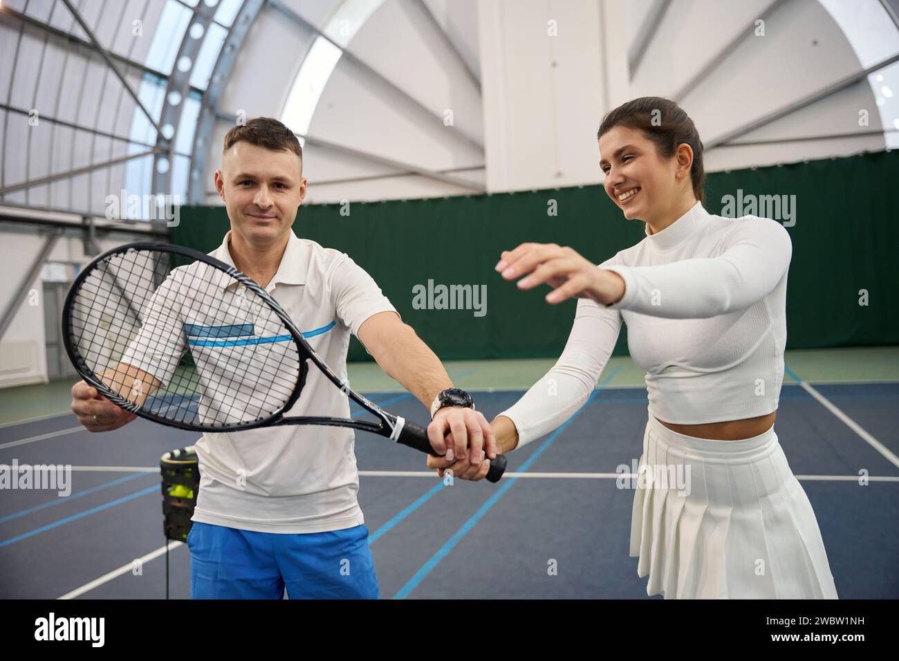 Young man teaching woman how to grip tennis racket Stock Photo - Alamy