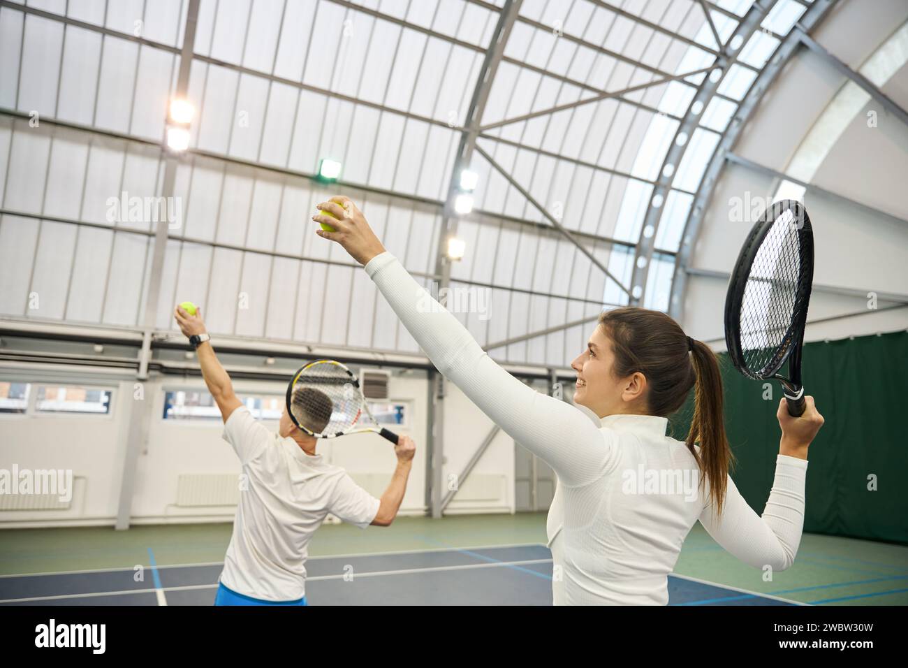 Man coach explaining serving technique to female player during tennis ...