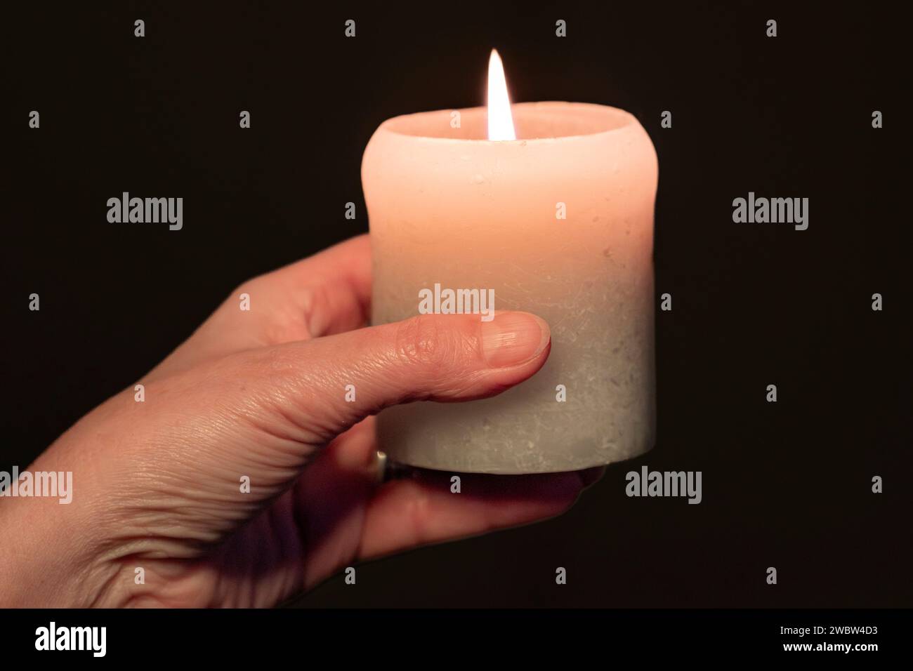 A hand holds a candle in the dark Stock Photo - Alamy