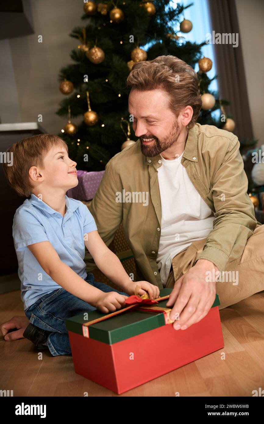 Father and son opening Christmas present box celebrating New Year in ...