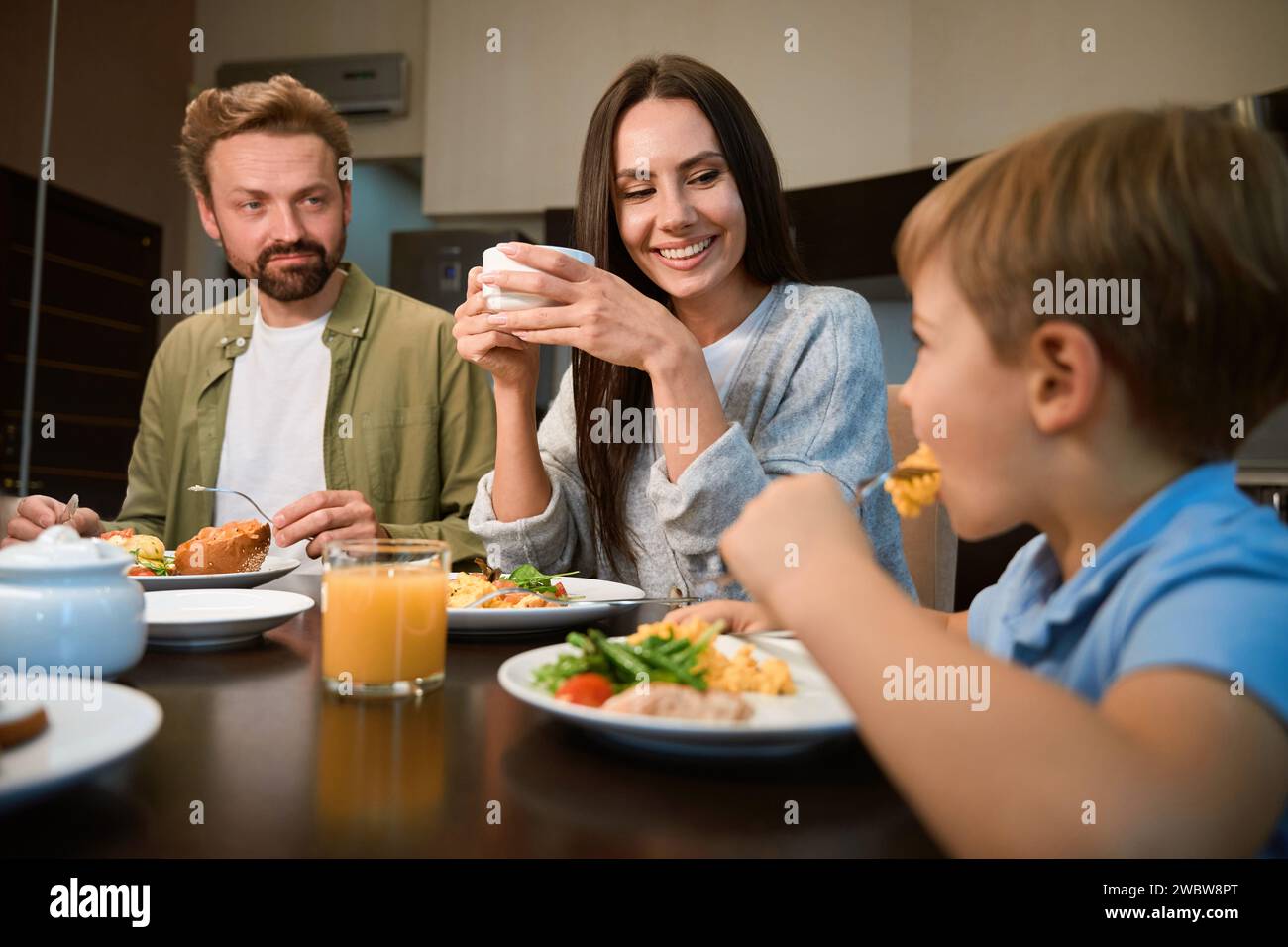 Woman drinking morning coffee while having breakfast with her family in ...