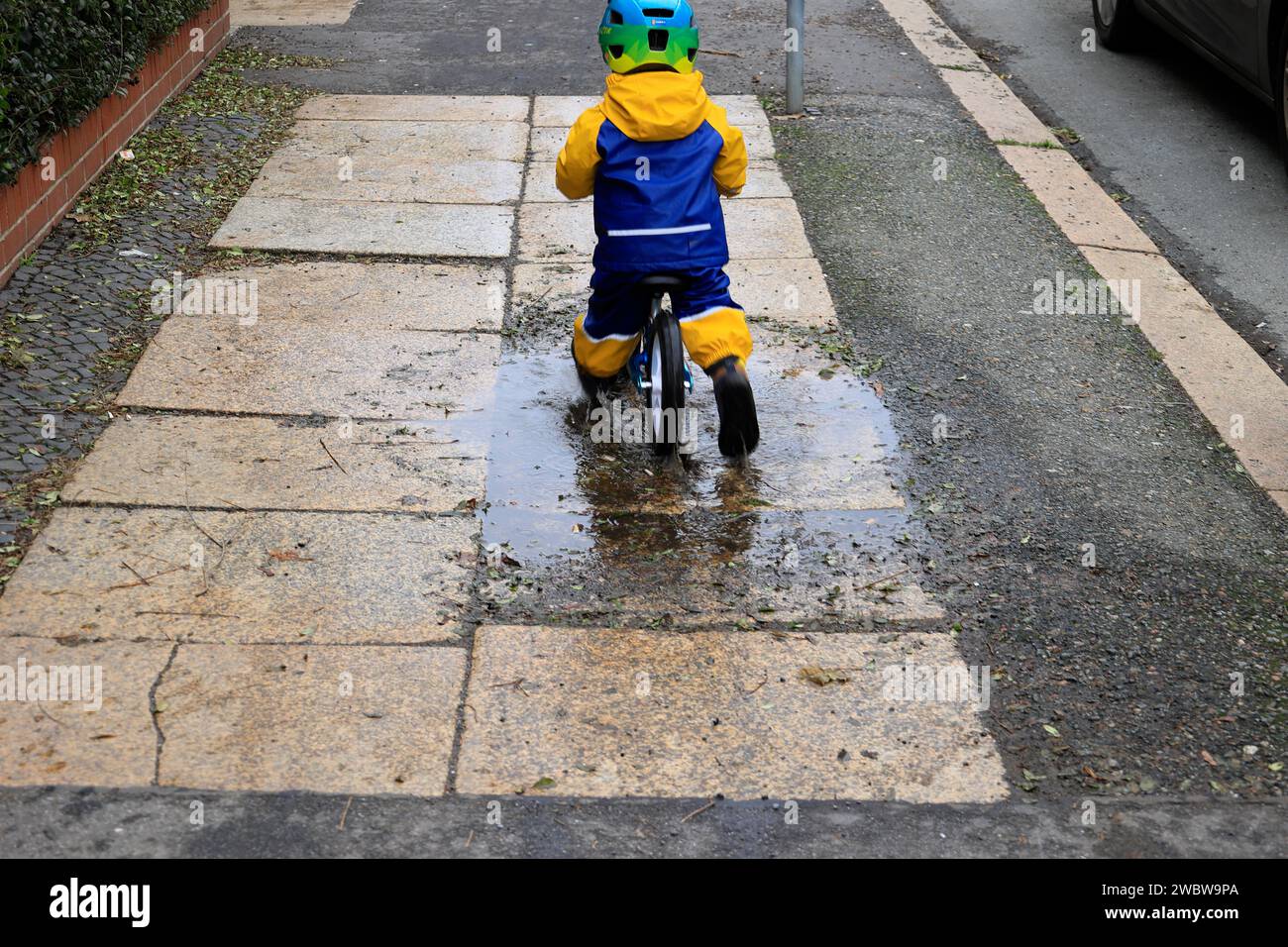 Small child rides a balance bike through a puddle Stock Photo - Alamy