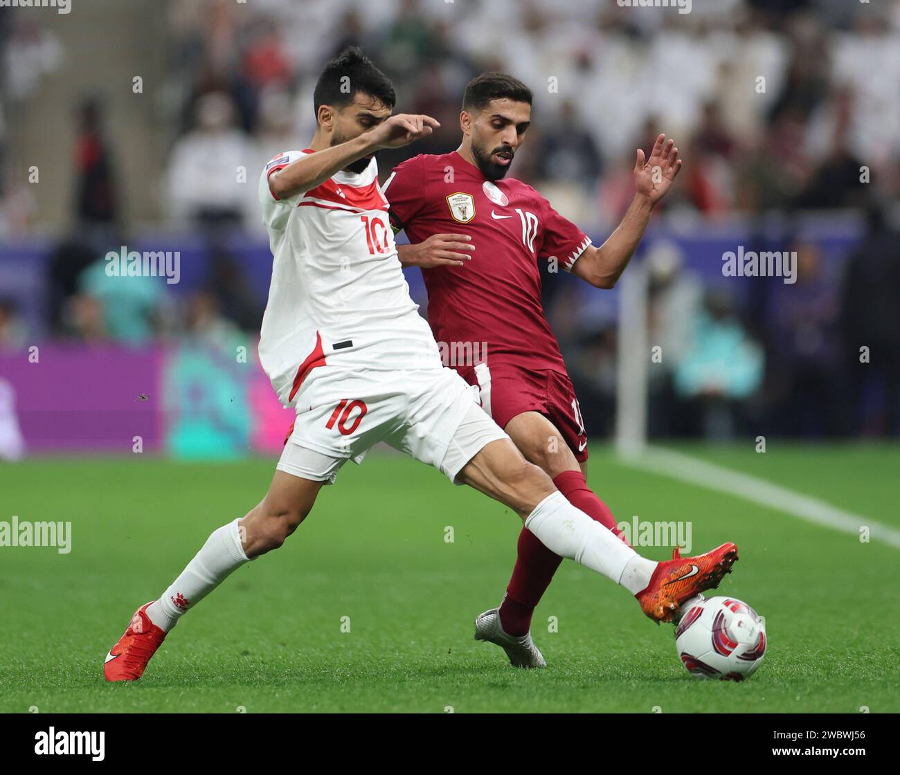 Lusail, Qatar. 12th Jan, 2024. Hasan Al Haydos (R) of Qatar vies with ...