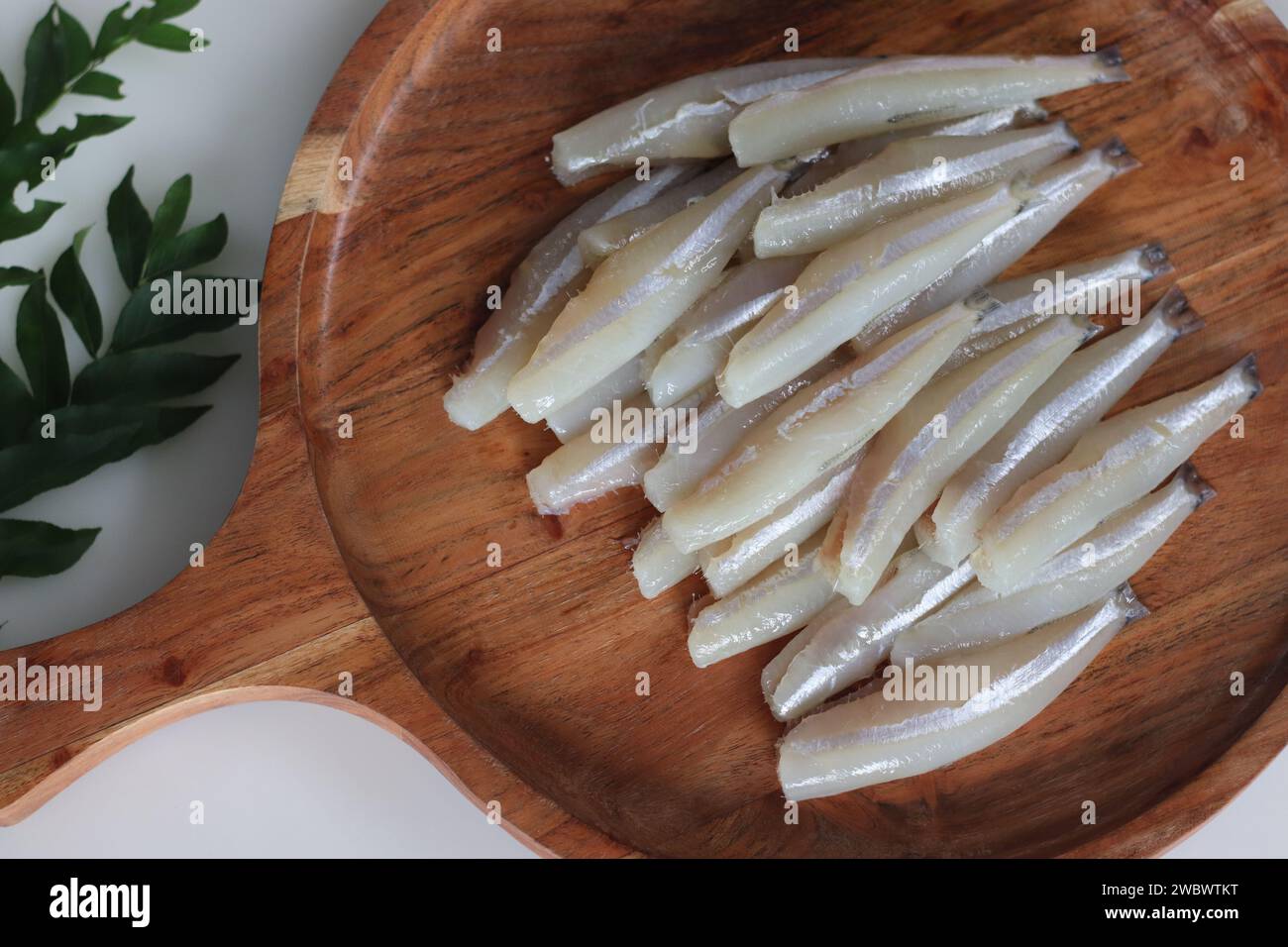 Freshly cut and cleaned anchovy fish presented on a rustic wooden tray ...