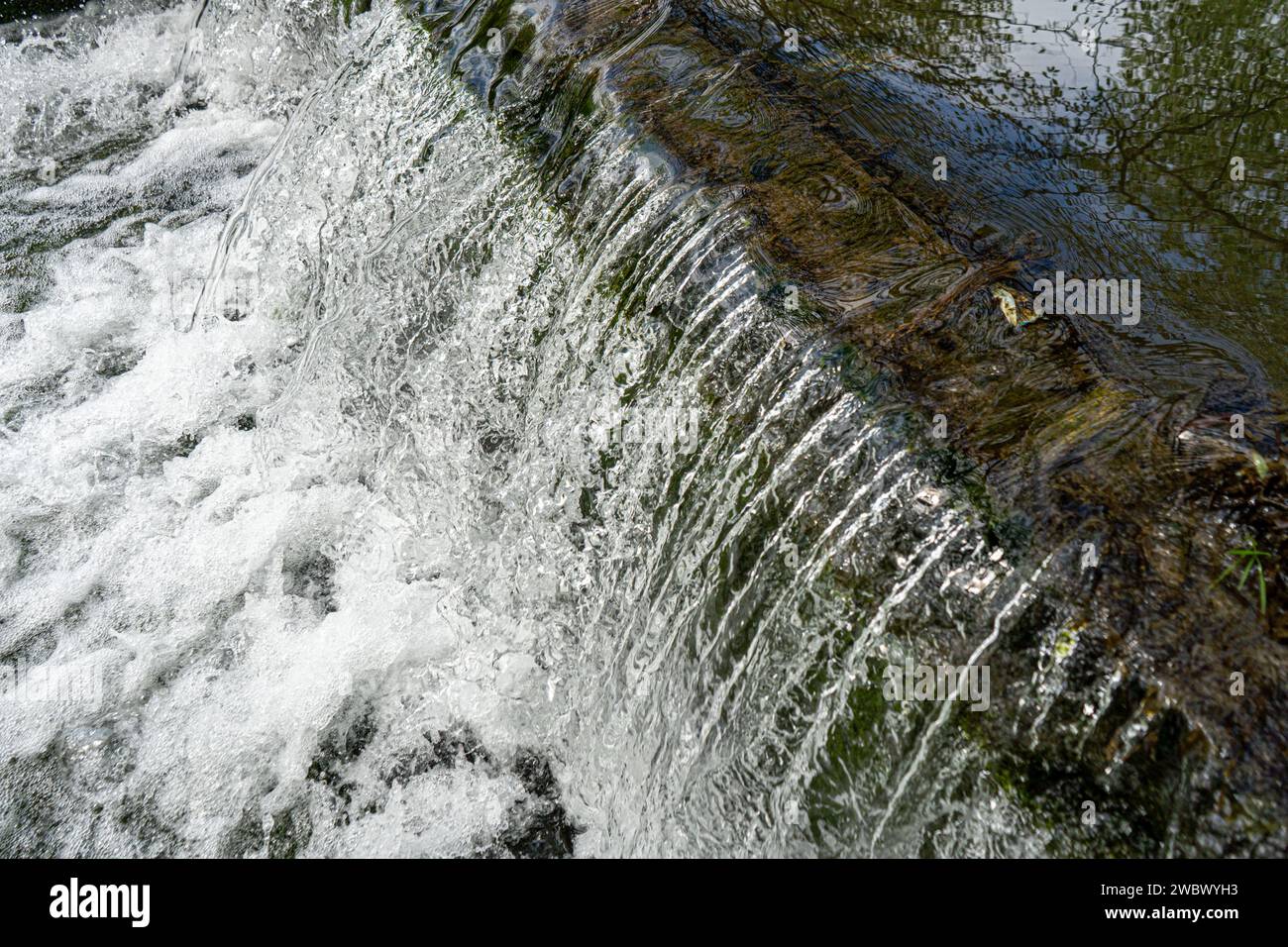 Cascading water over weir showing white foaming water Stock Photo - Alamy