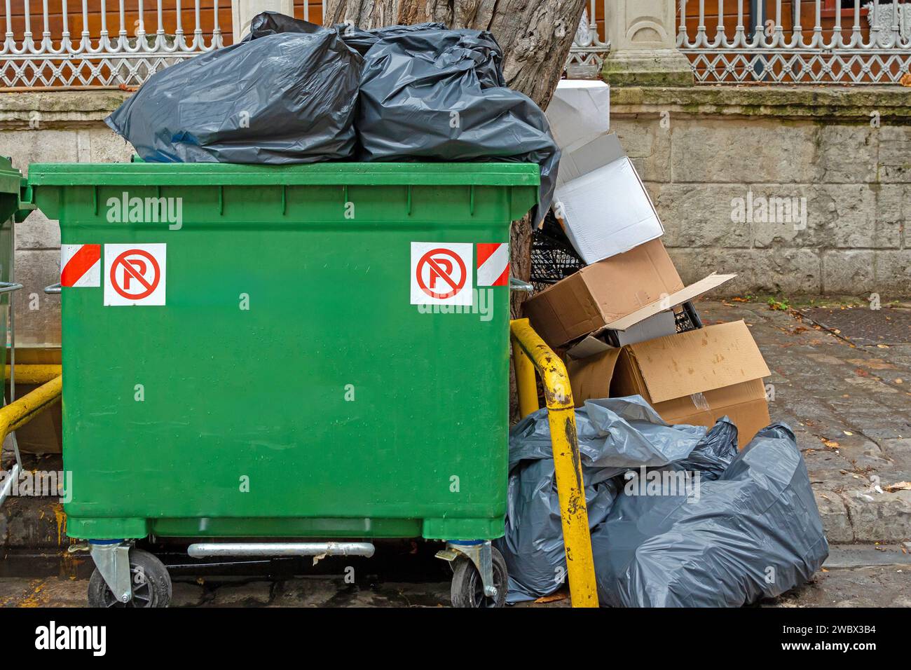 Pile of garbage standing next to a plastic container outside on a ...