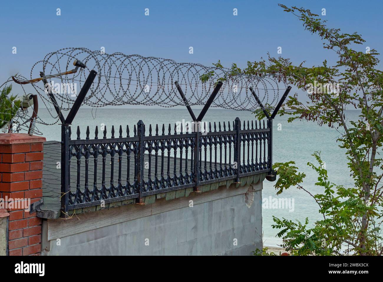 Metal razor wire safety fence outside house property Stock Photo - Alamy
