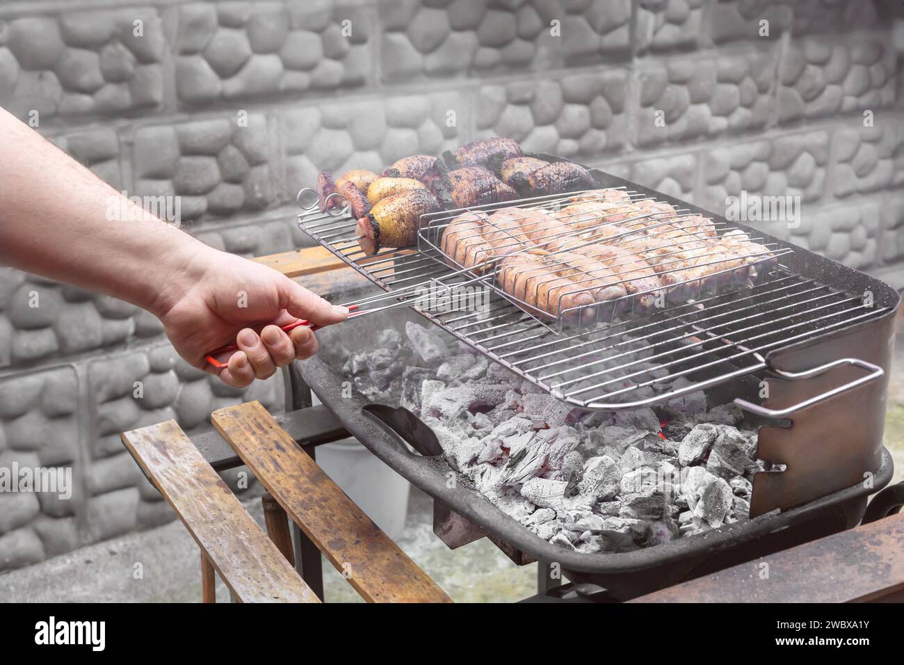 Hand turning meat sausages on a charcoal bbq grill Stock Photo - Alamy