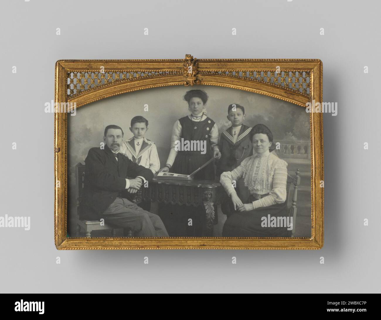 Group portrait of an unknown family, around a table with a photo album ...