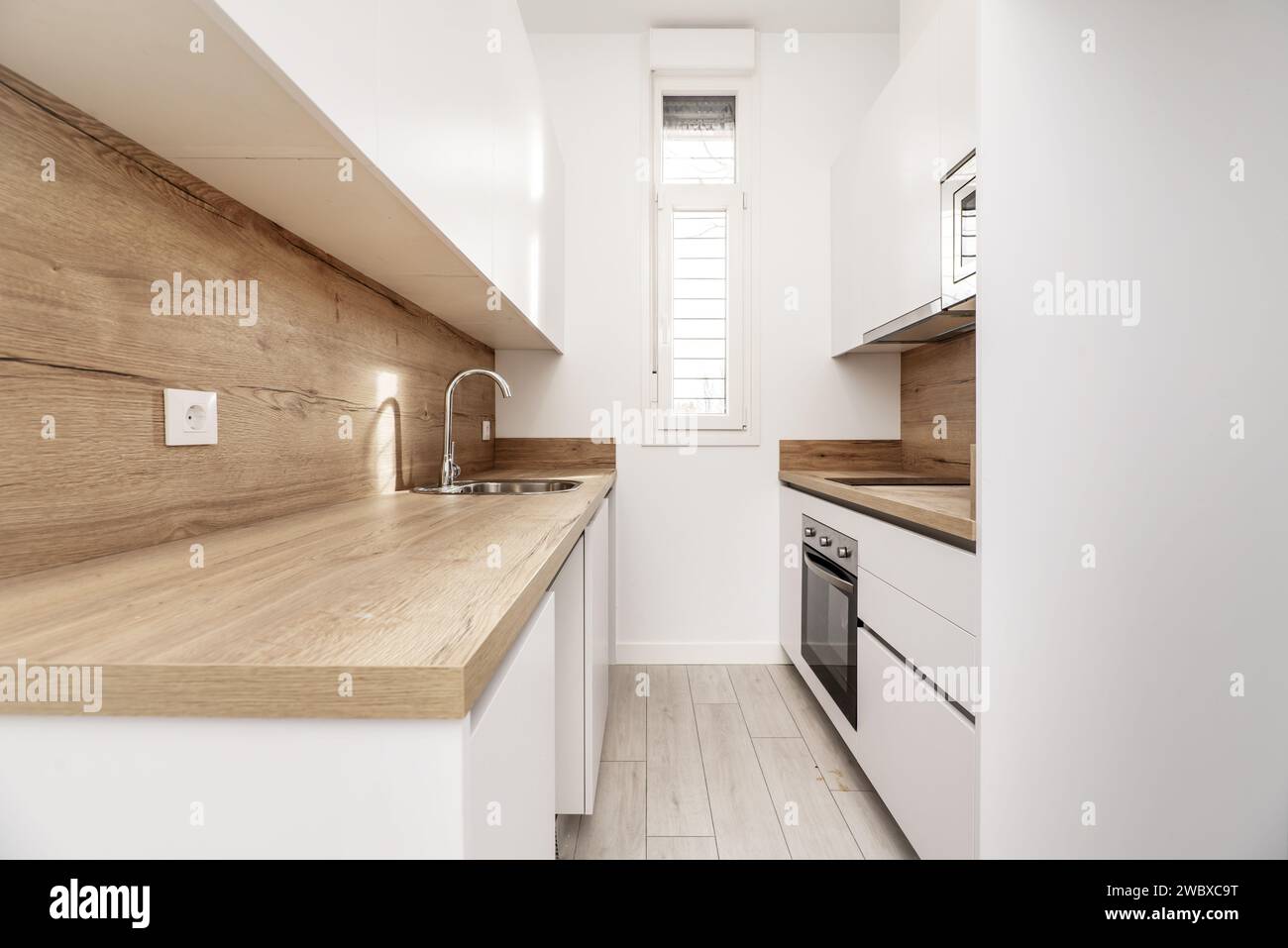 Newly installed small kitchen with plain white cabinets, light wood ...