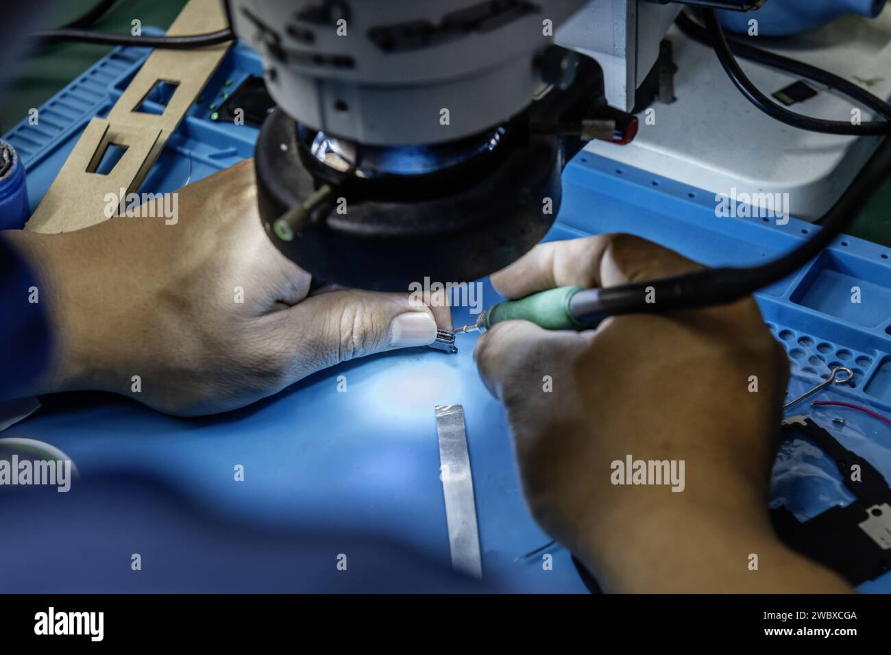 The hands of an electronic repair shop operator under an electron ...