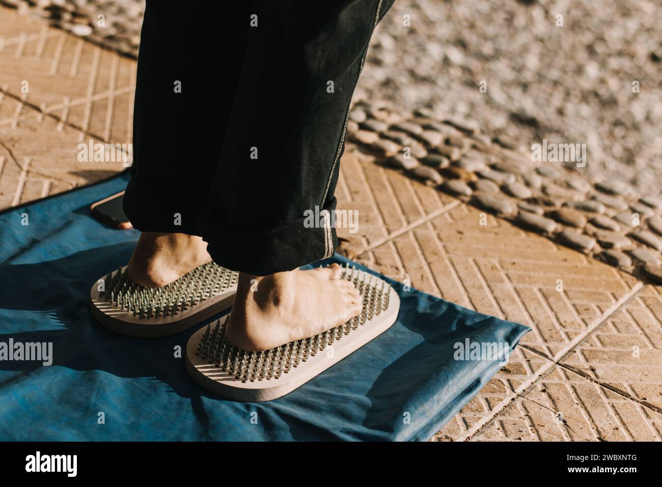 Feet standing on a Sadhu board (Yoga board) with sharp nails outdoor ...