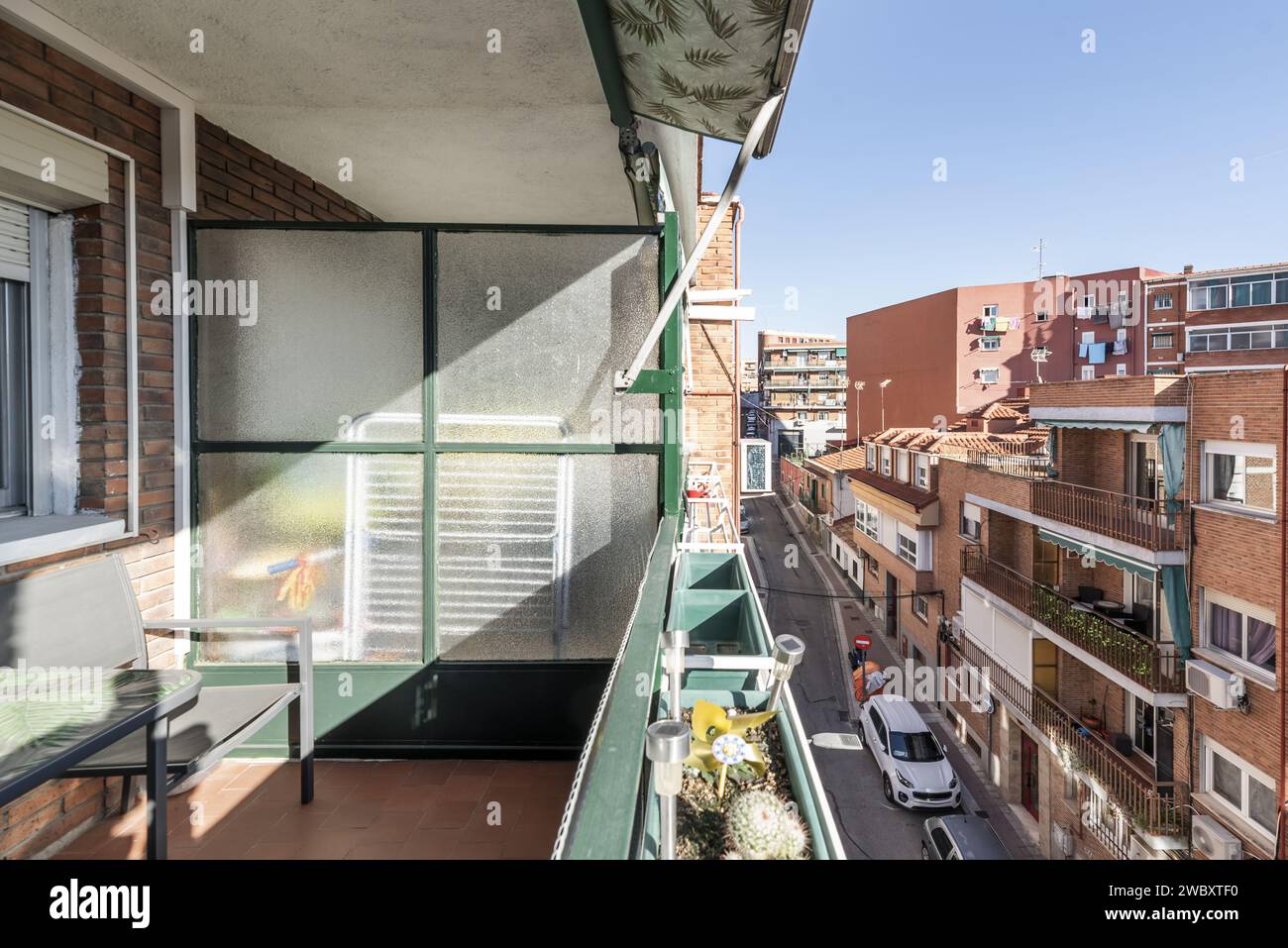 A small terrace with brown terrazzo floor, metal railing painted green ...