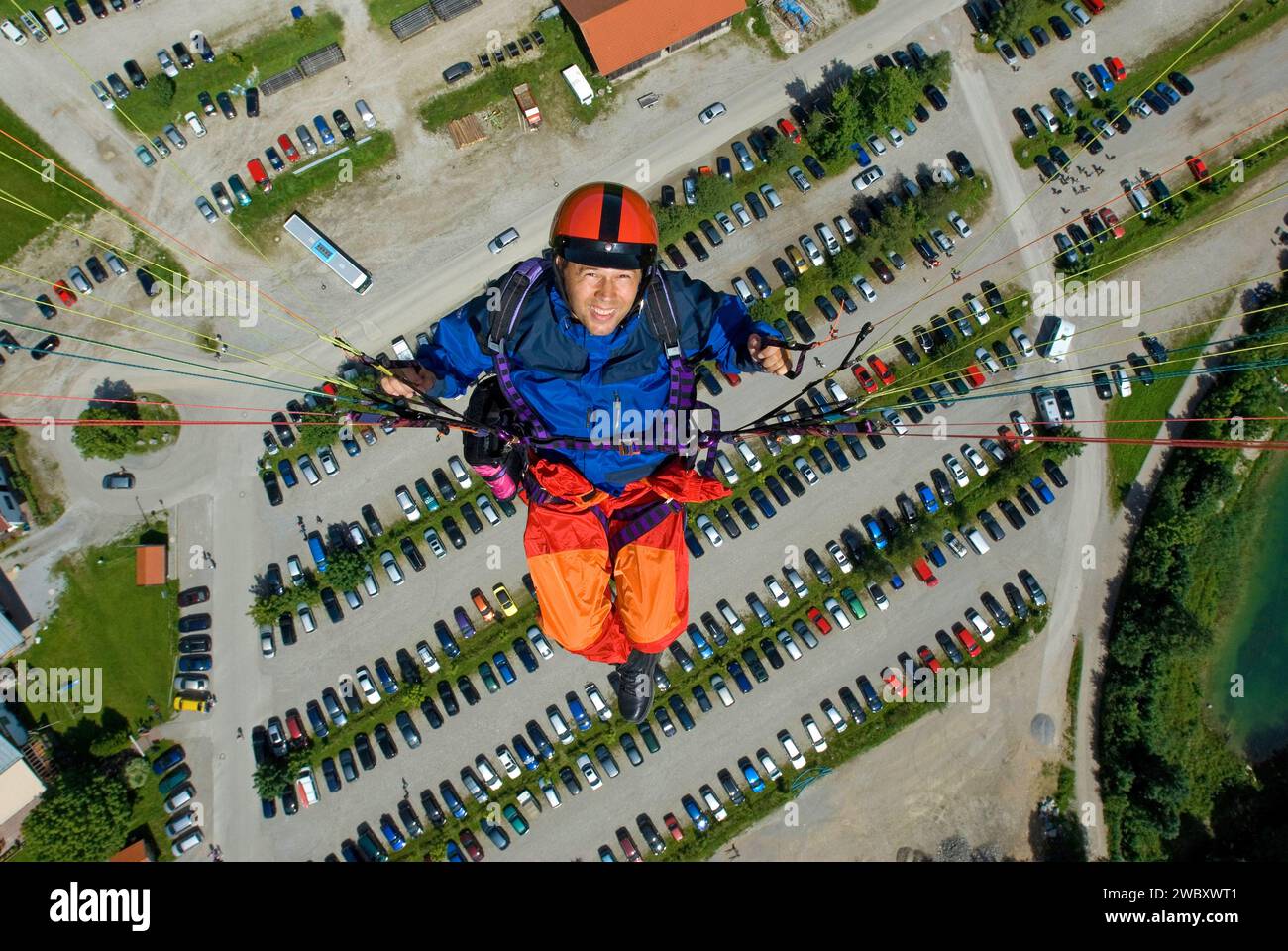 paragliding pilot with orange and blue clothes, flying high over ...