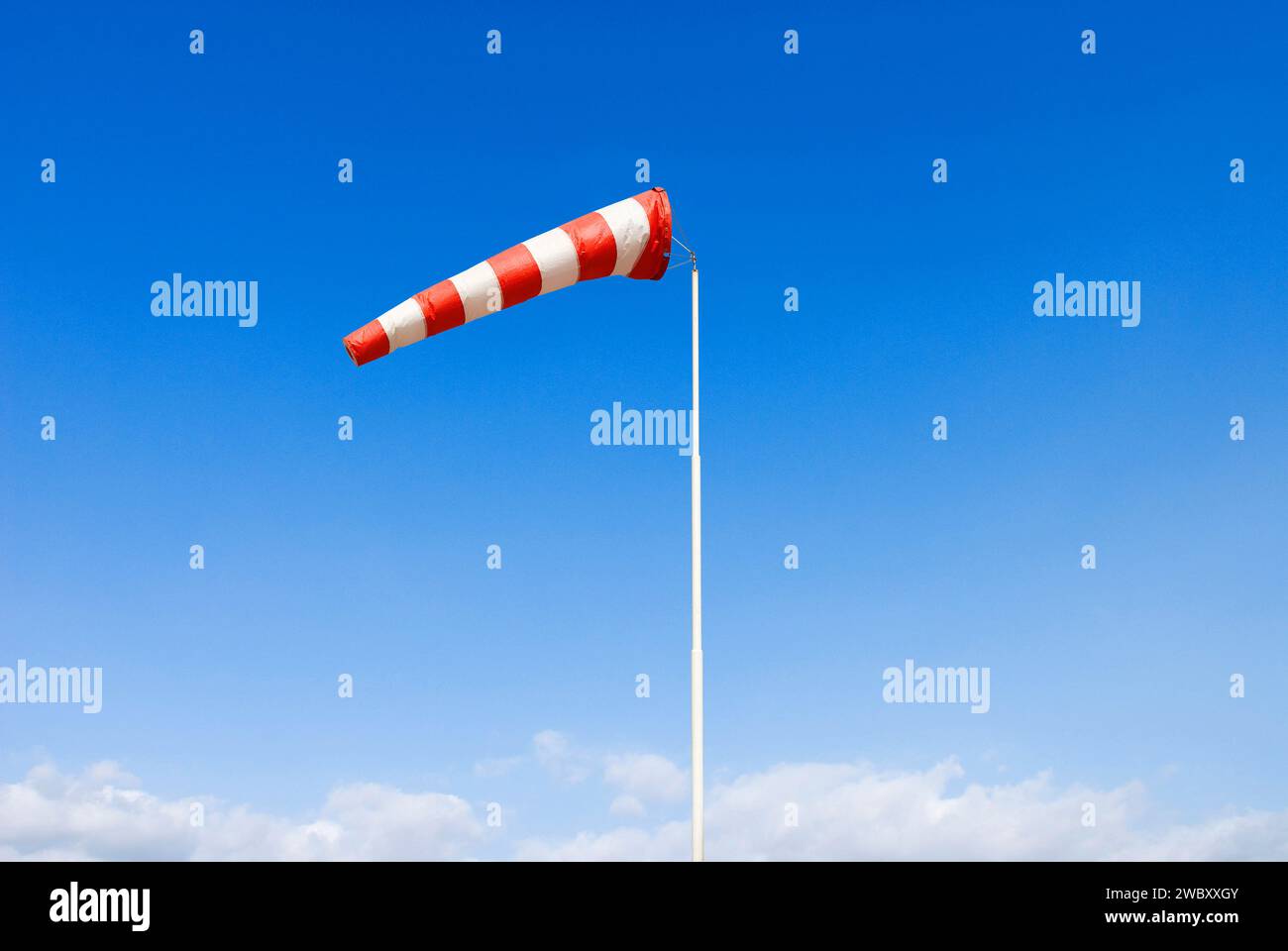 wind sock in blue sky, red and white, indicating moderate wind Stock ...