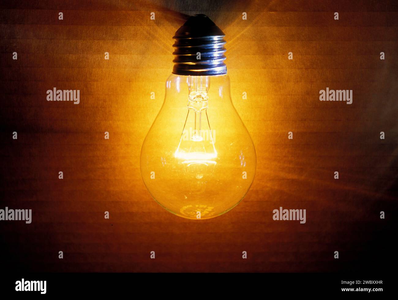 closeup of an old burning light bulb, lamp socket, a carton as ...