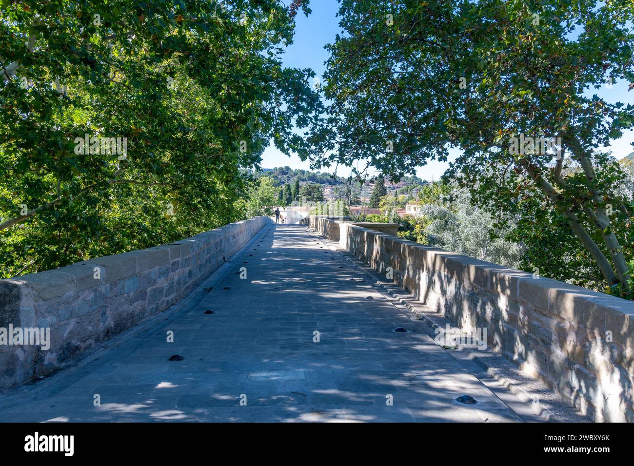Stone footbridge from above with neatly worked stone and a stone parapet on both sides. Small ...