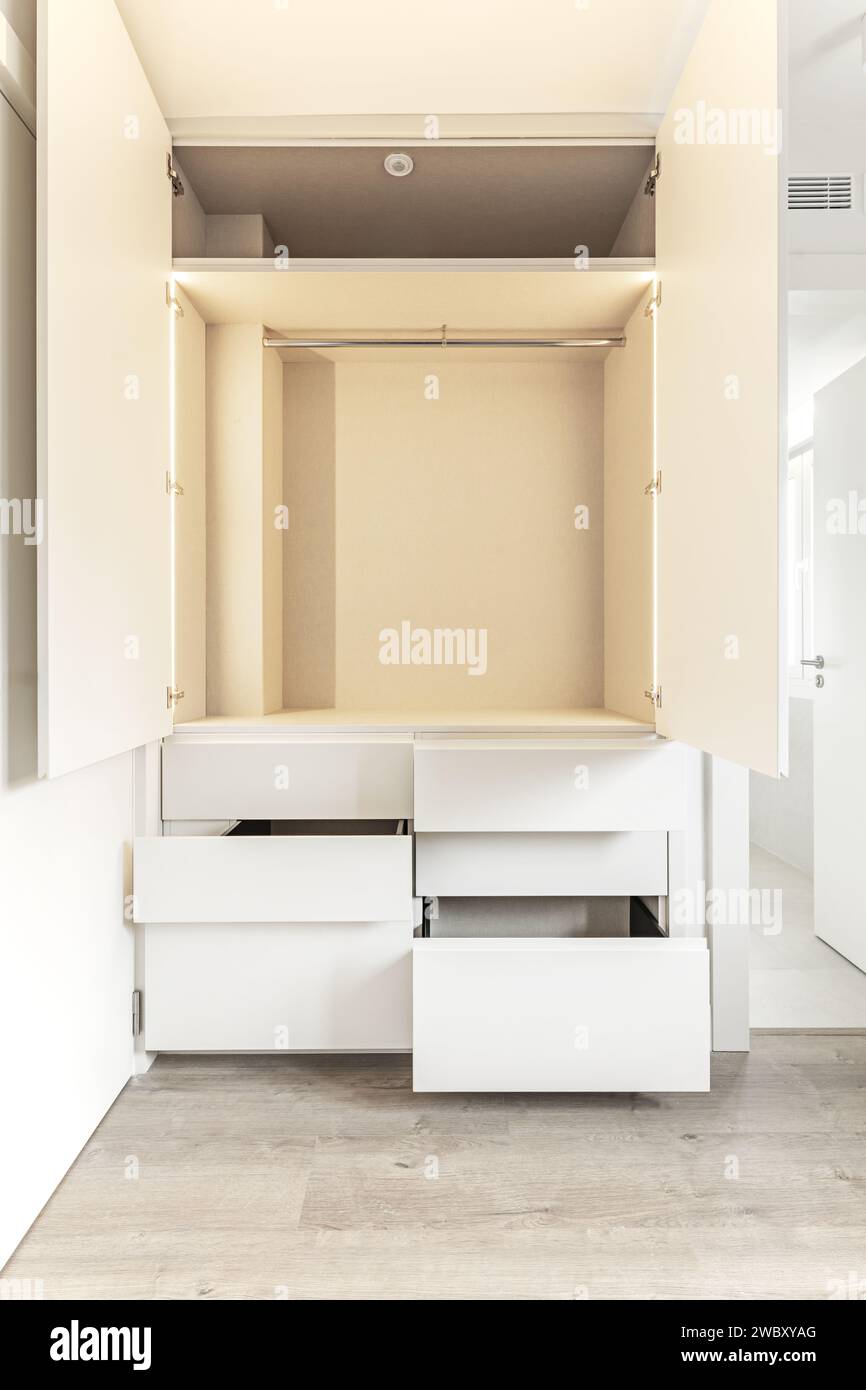 A newly renovated room with white wooden cabinets with open doors and ...