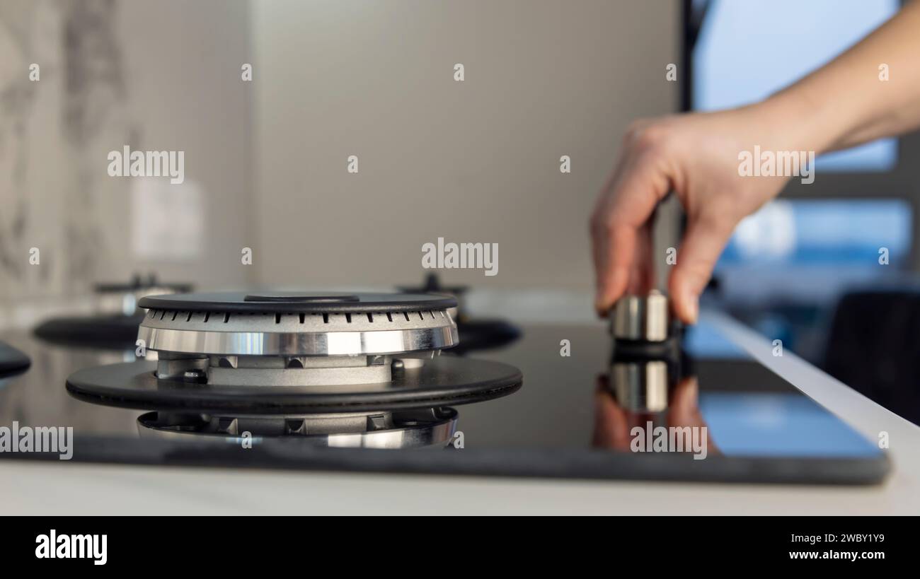 A woman's hand lights a gas stove in the kitchen. Turn gas on or off ...