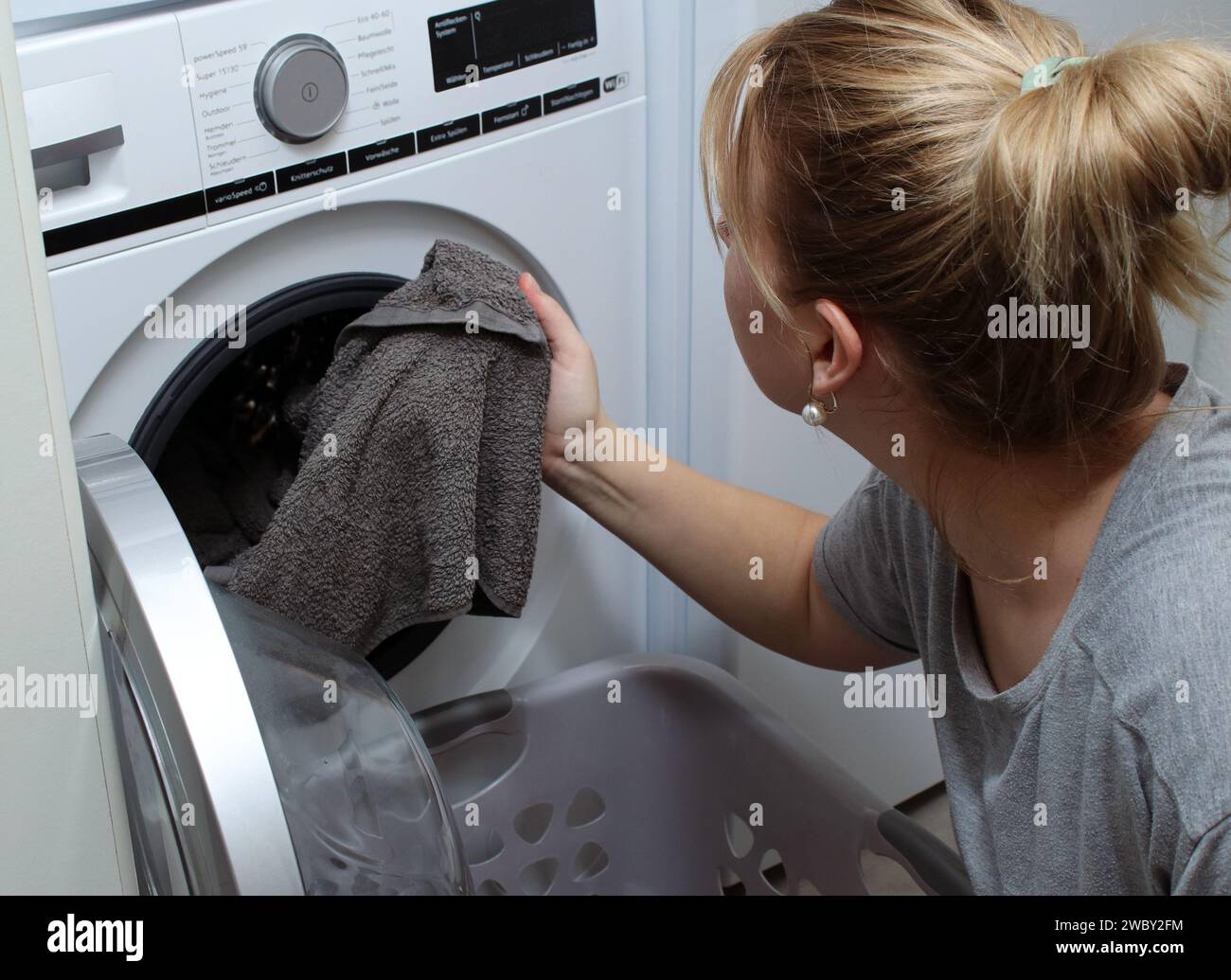 Close up of a caucasian woman taking clothes out of a washing machine ...