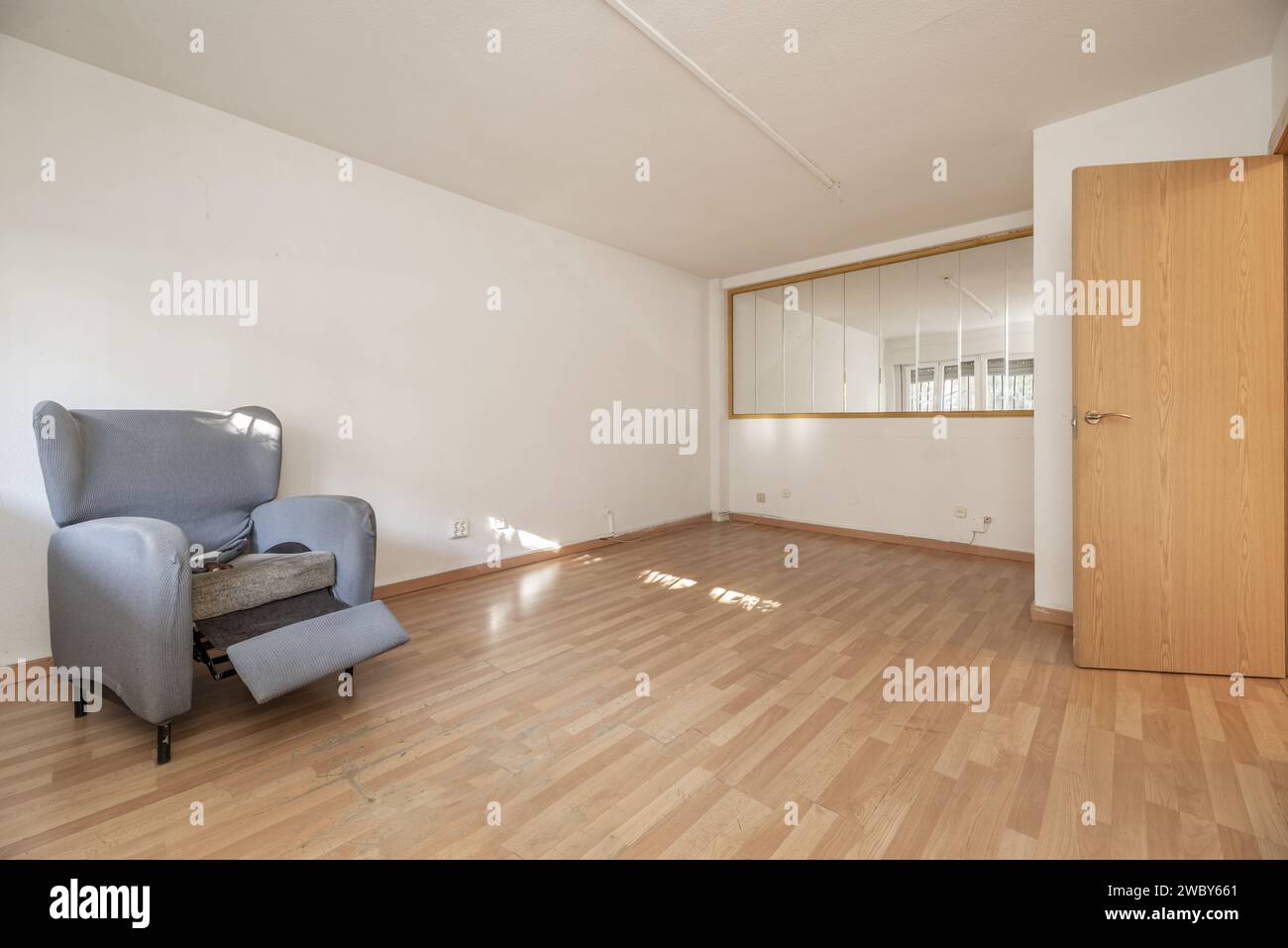 Empty living room with an old single sofa and mirror panels on a wall ...