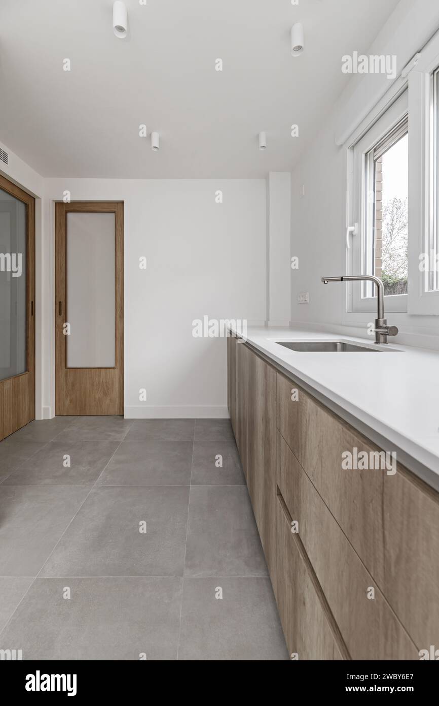 Newly renovated kitchen with wooden furniture and synthetic white stone ...