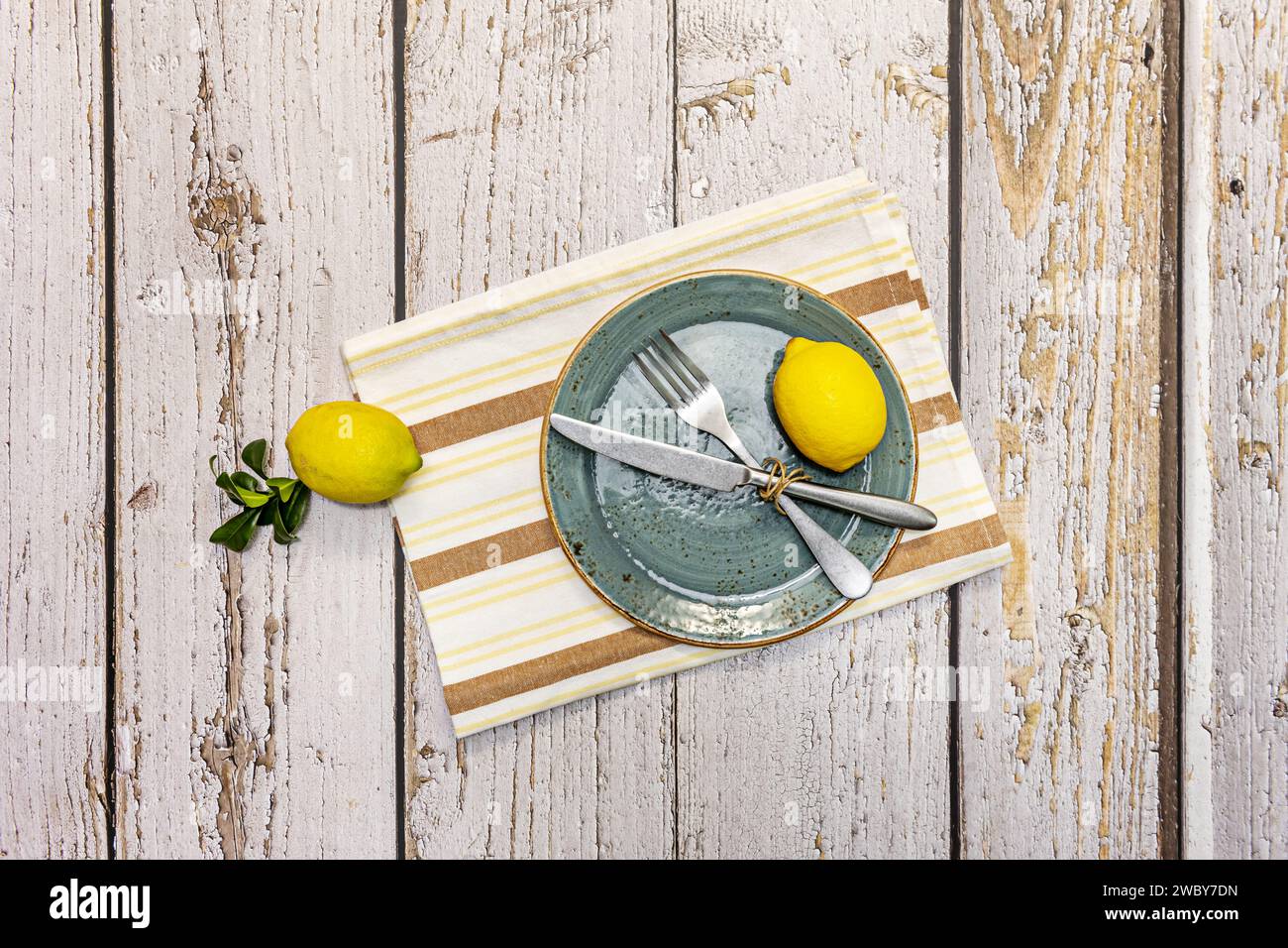 still life with porcelain plates with metal cutlery and some yellow ...
