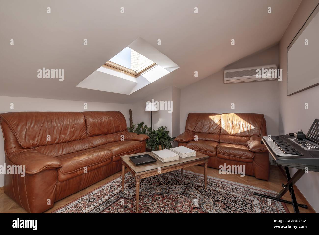 An office inside an attic room with a skylight in the ceiling and a ...