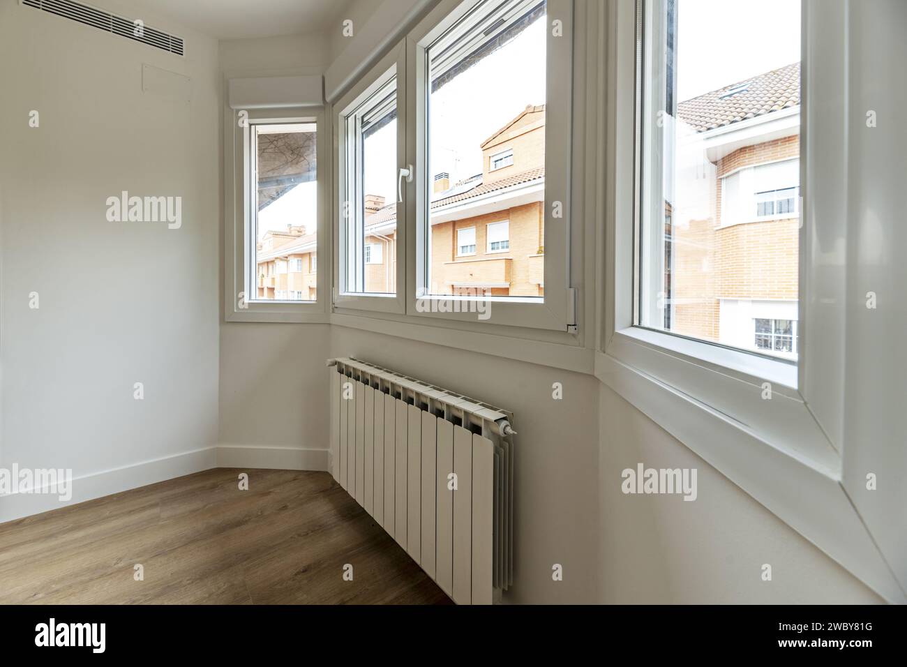 An empty room with a gallery full of windows with aluminum radiators ...