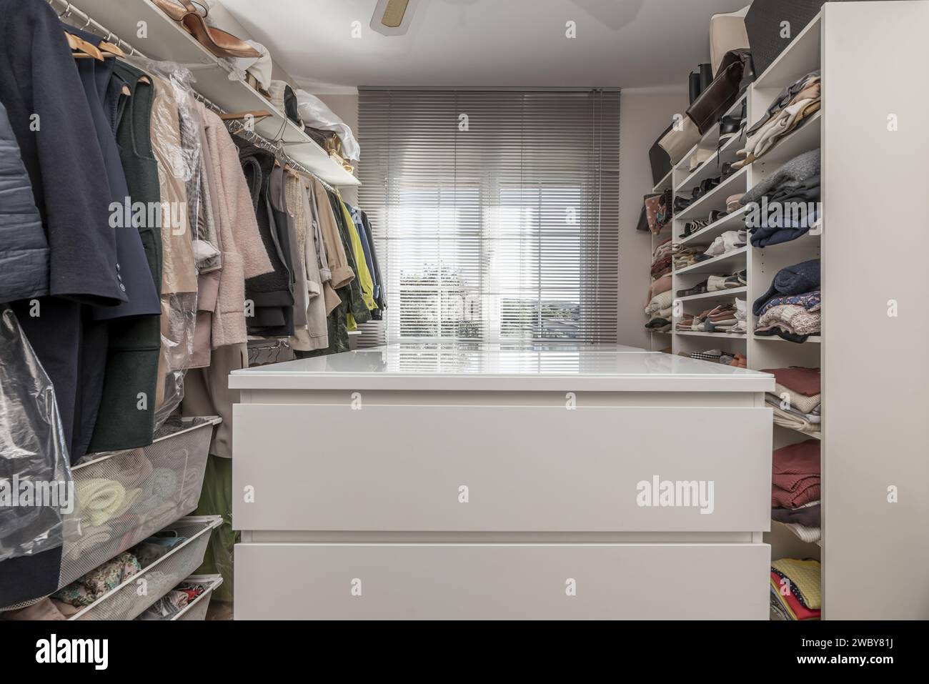 A room dedicated to a dressing room with white wooden shelves, bars for ...