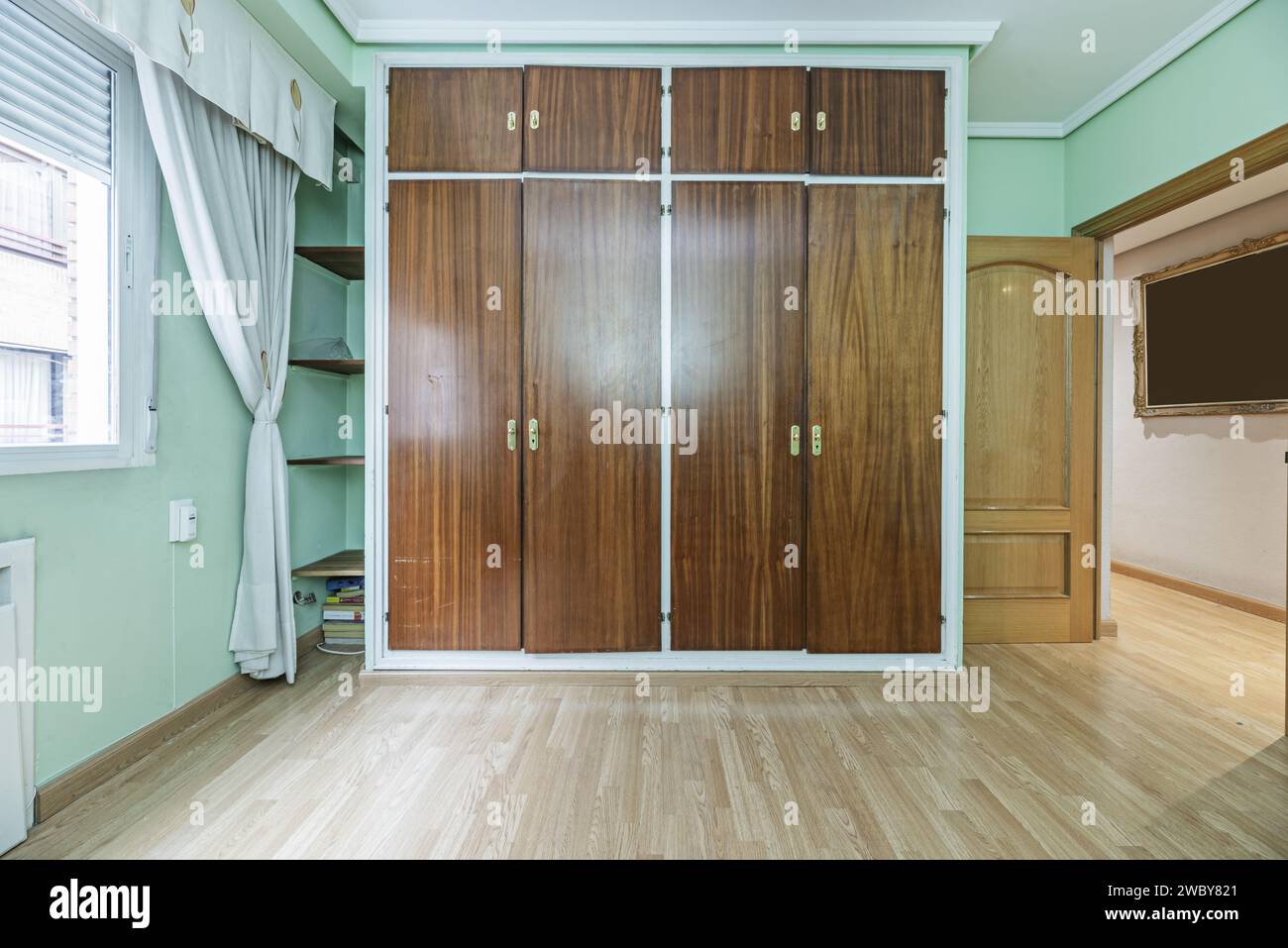 An empty room with light green painted walls, plaster moldings on the ...