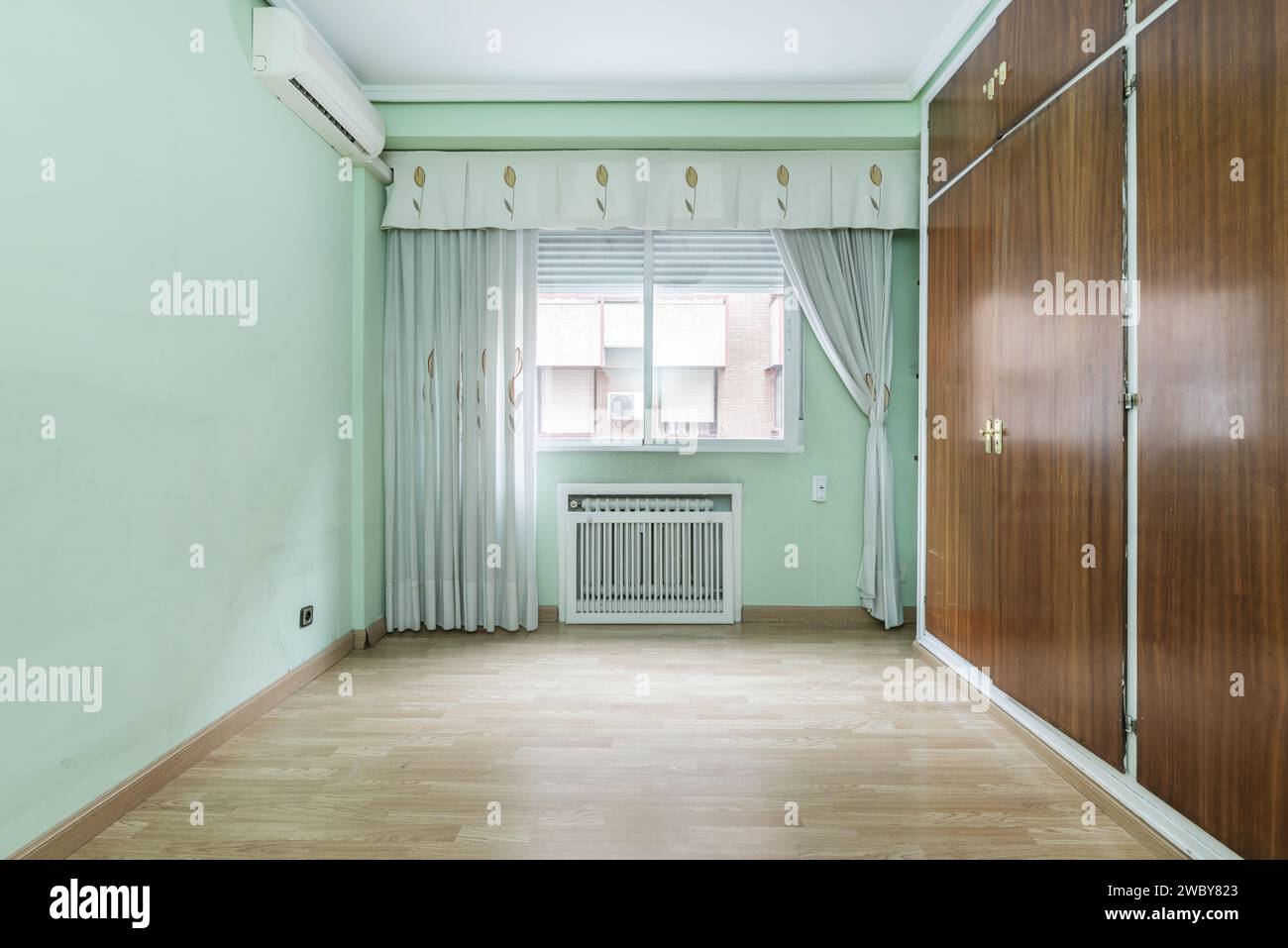 Room with green walls, matching curtains, white radiator covers and a ...