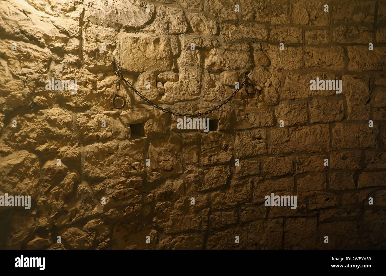 Slavery and bondage strong steel old shackles on stone wall in castle ...