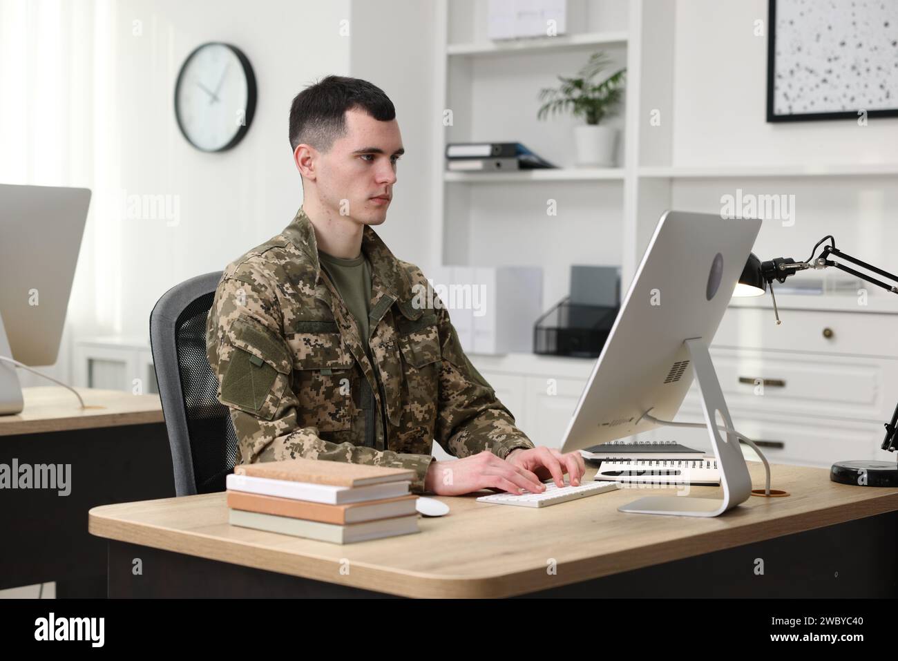 Military education. Young student in soldier uniform learning at wooden ...