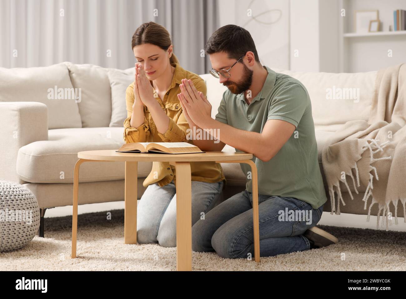 Family couple praying over Bible together at table indoors Stock Photo ...