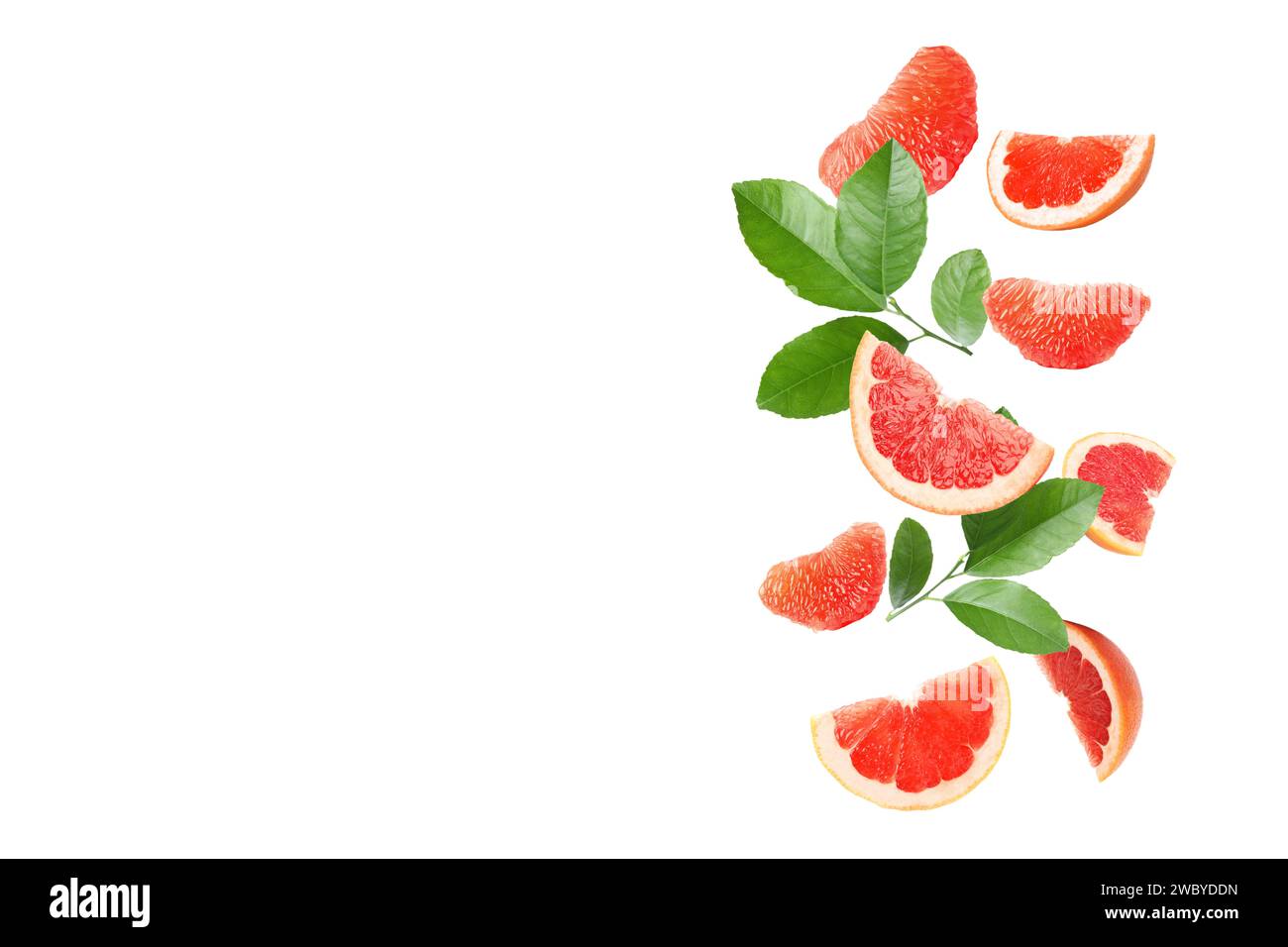 Fresh grapefruit pieces and green leaves falling on white background ...