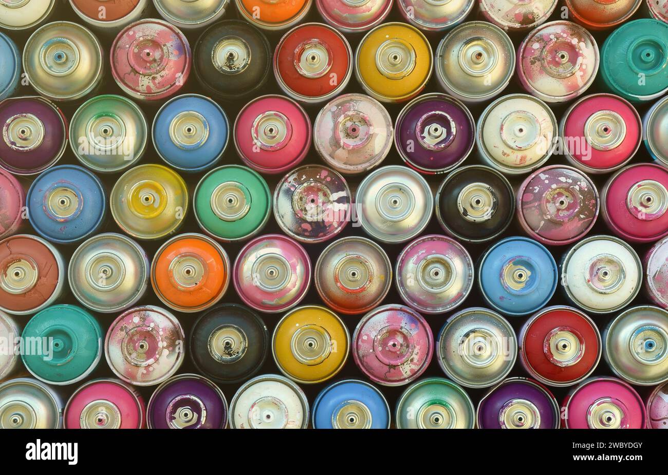 Large number of used colorful spray cans of aerosol paint lying on the ...