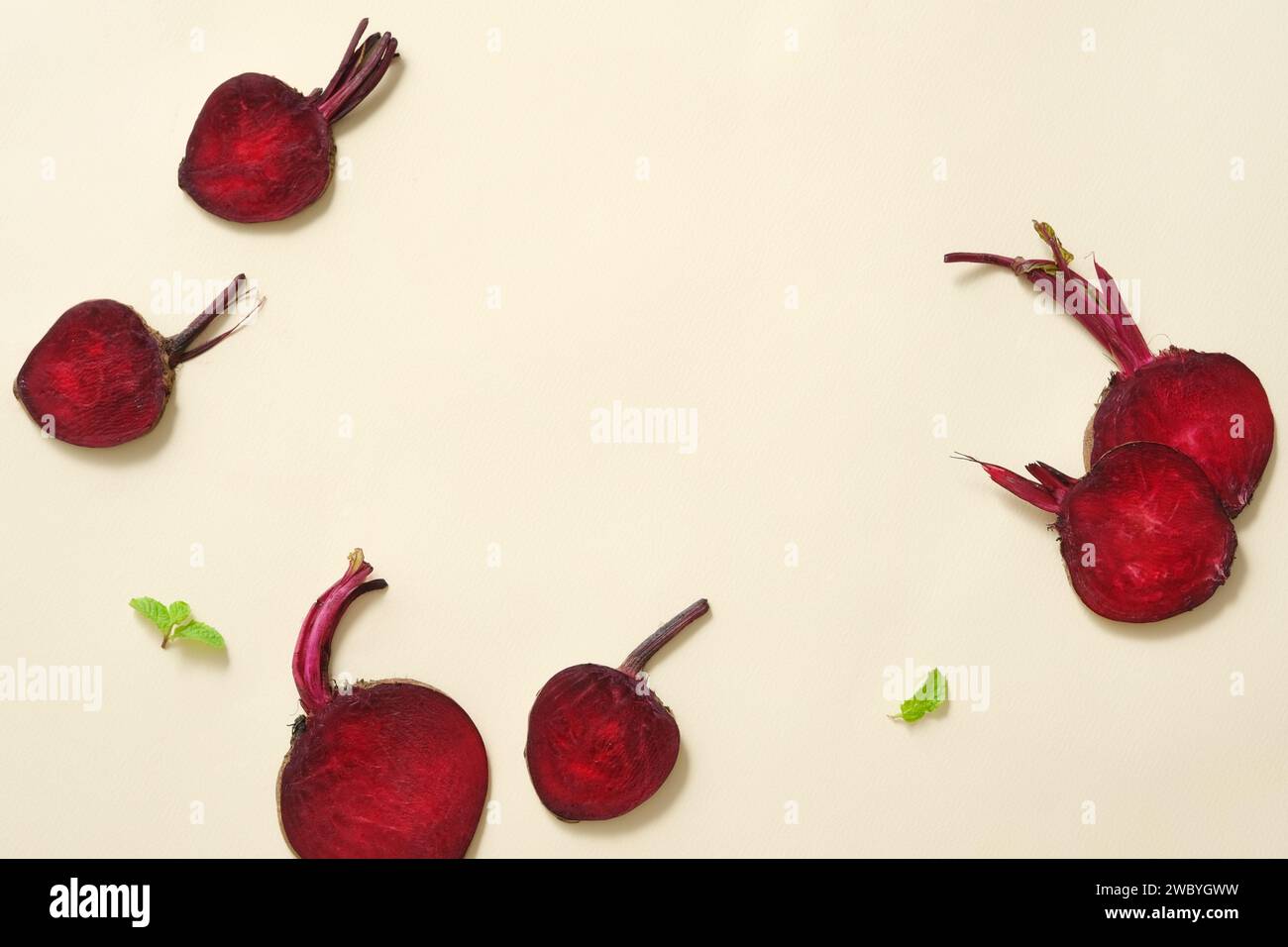 Slices of beetroot are arranged with small green leaves over light ...