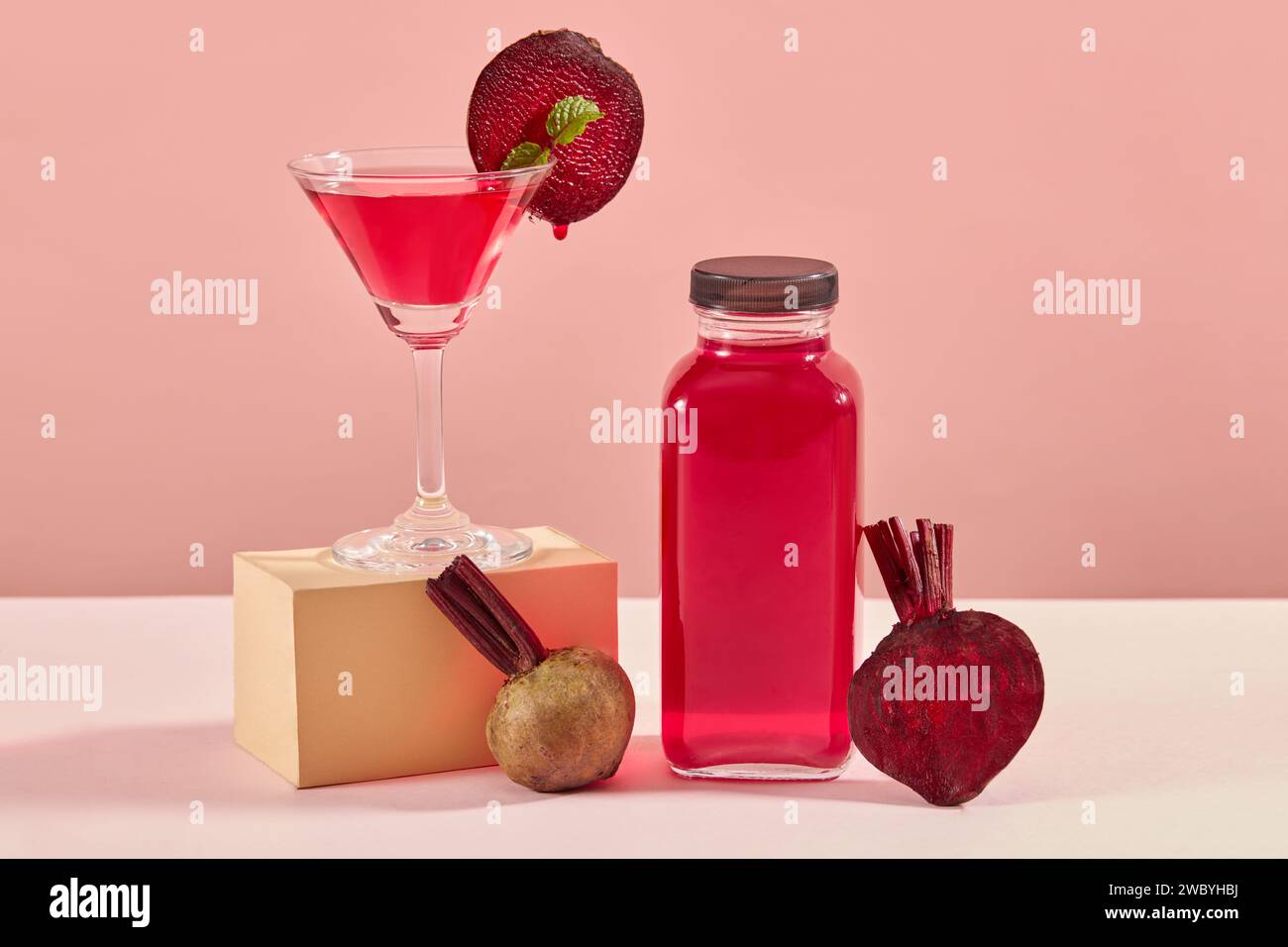 A cocktail glass and a bottle filled with beetroot juice decorated over ...