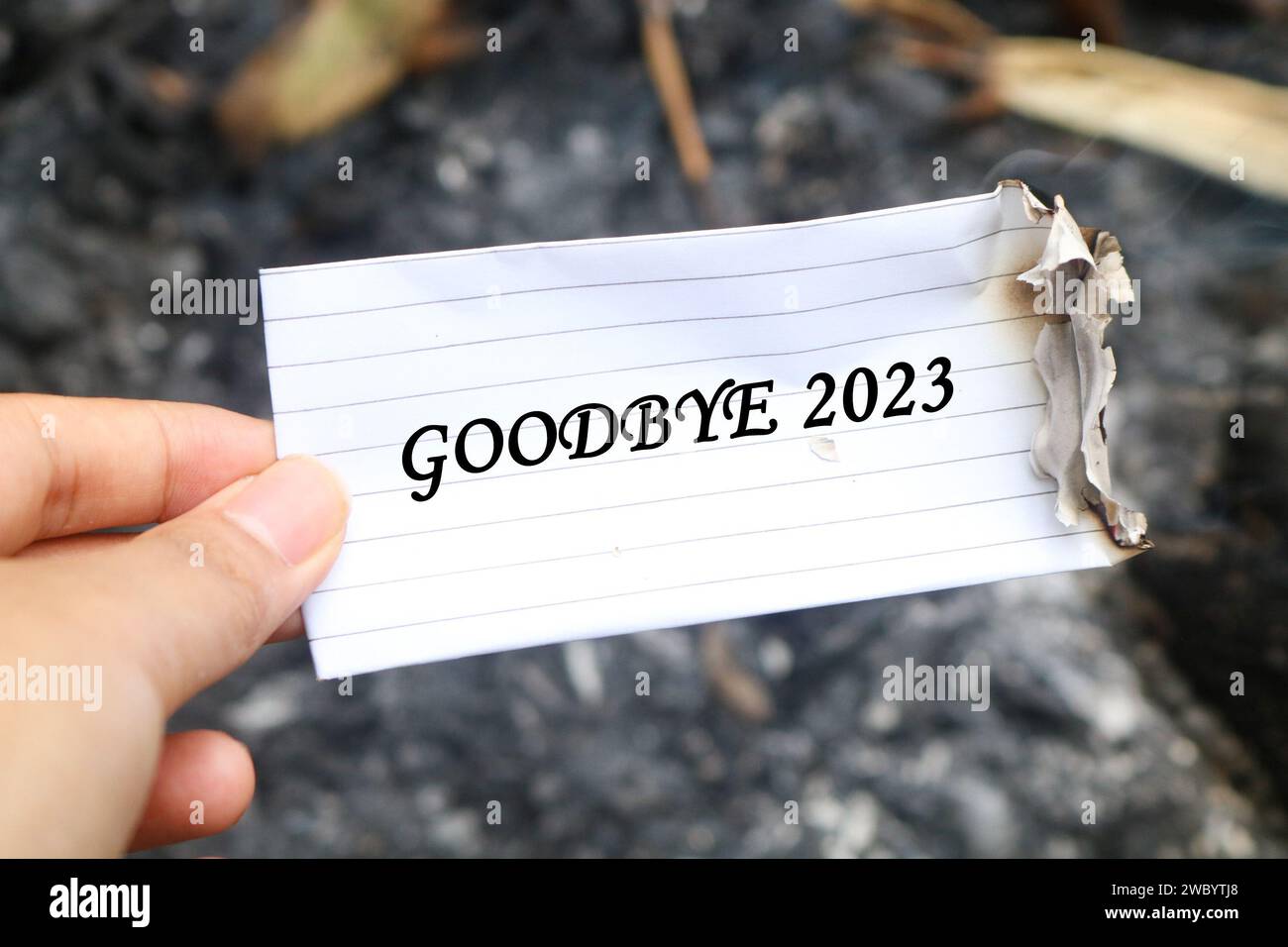 Hand holding half burnt note with writing Bye 2023. new life and new ...