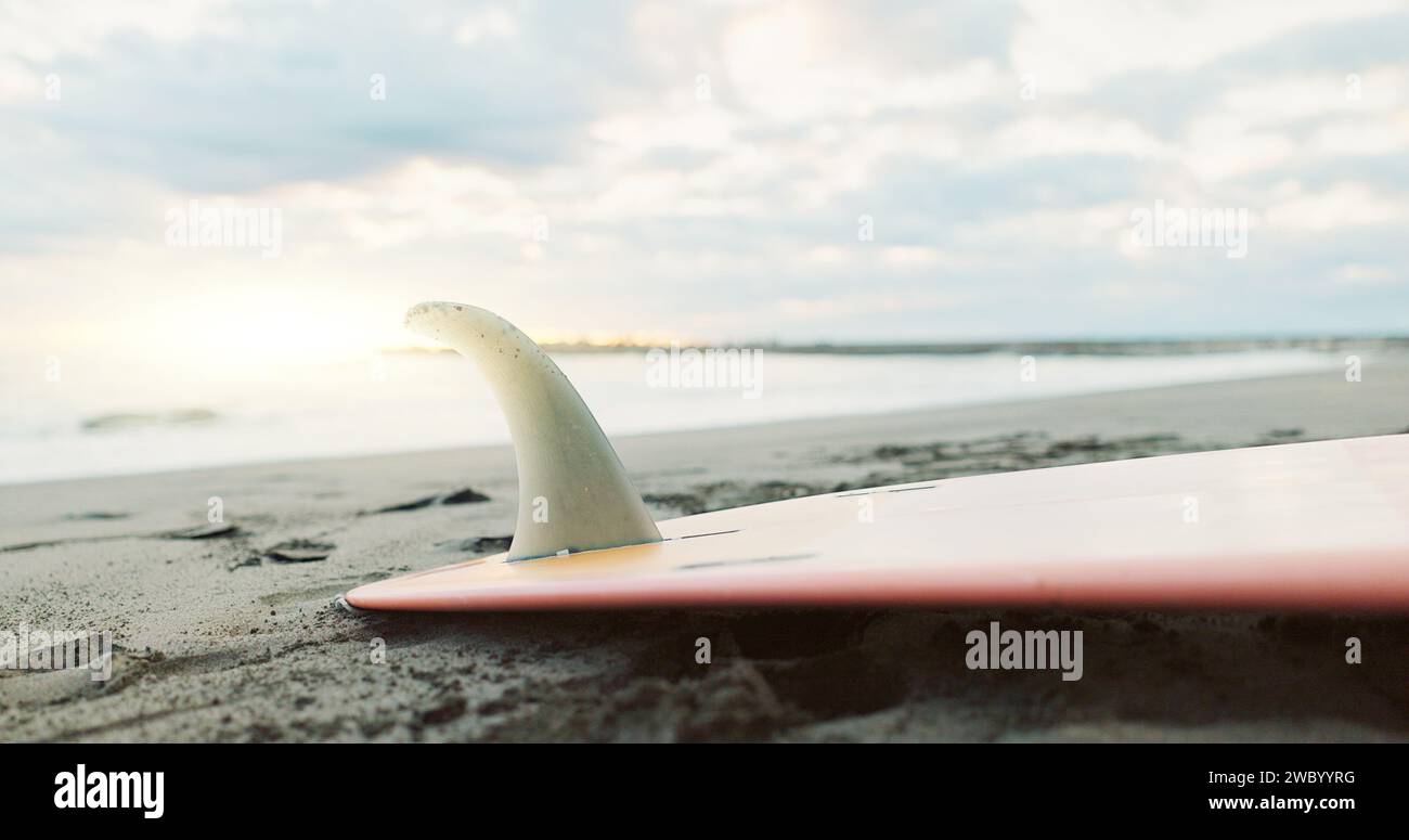 Beach, sand and surfboard at ocean water in the background on summer ...